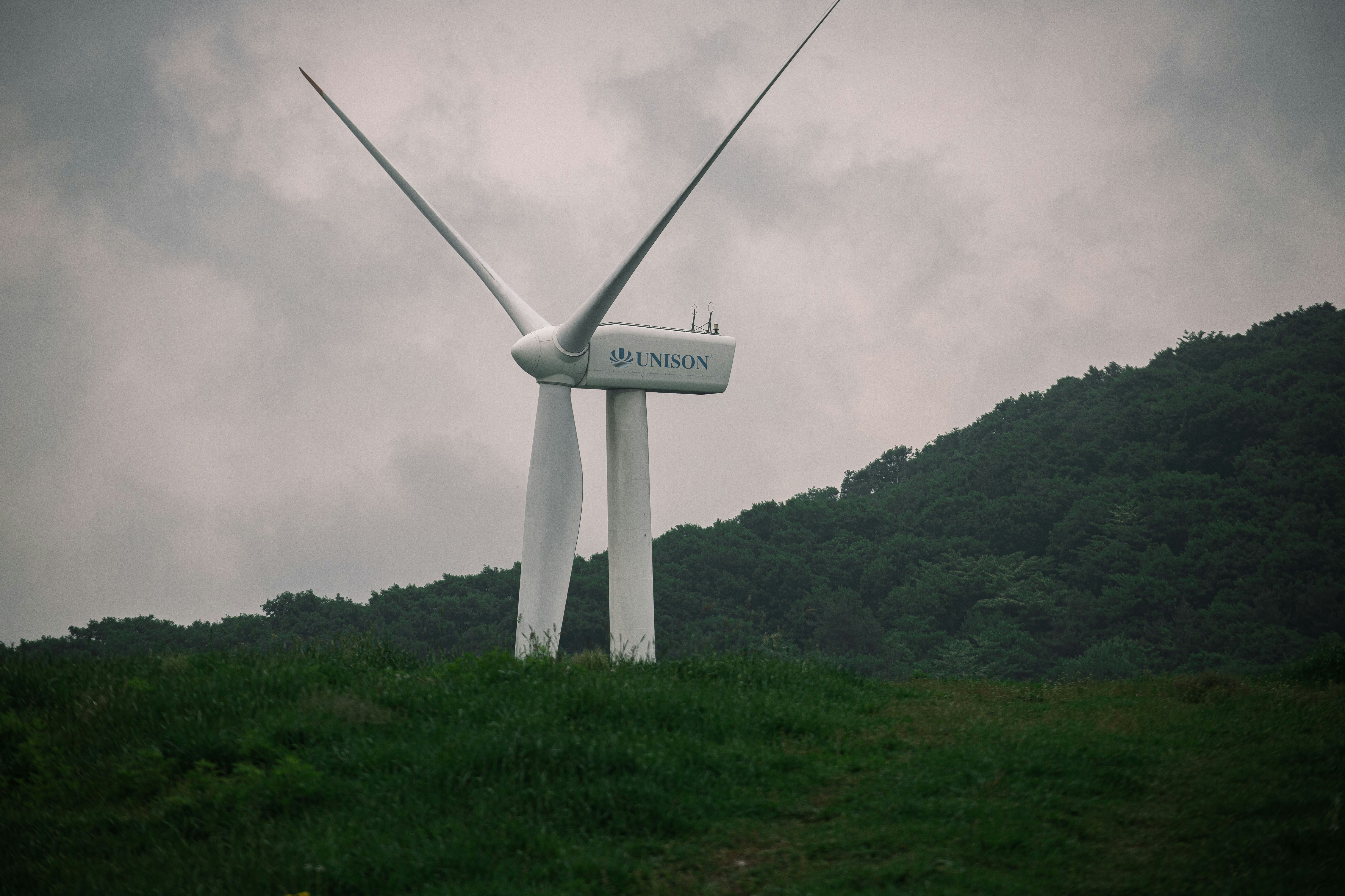 Rotor Silhouette on the Green Spine: Wind Turbine Under Cloudy Skies