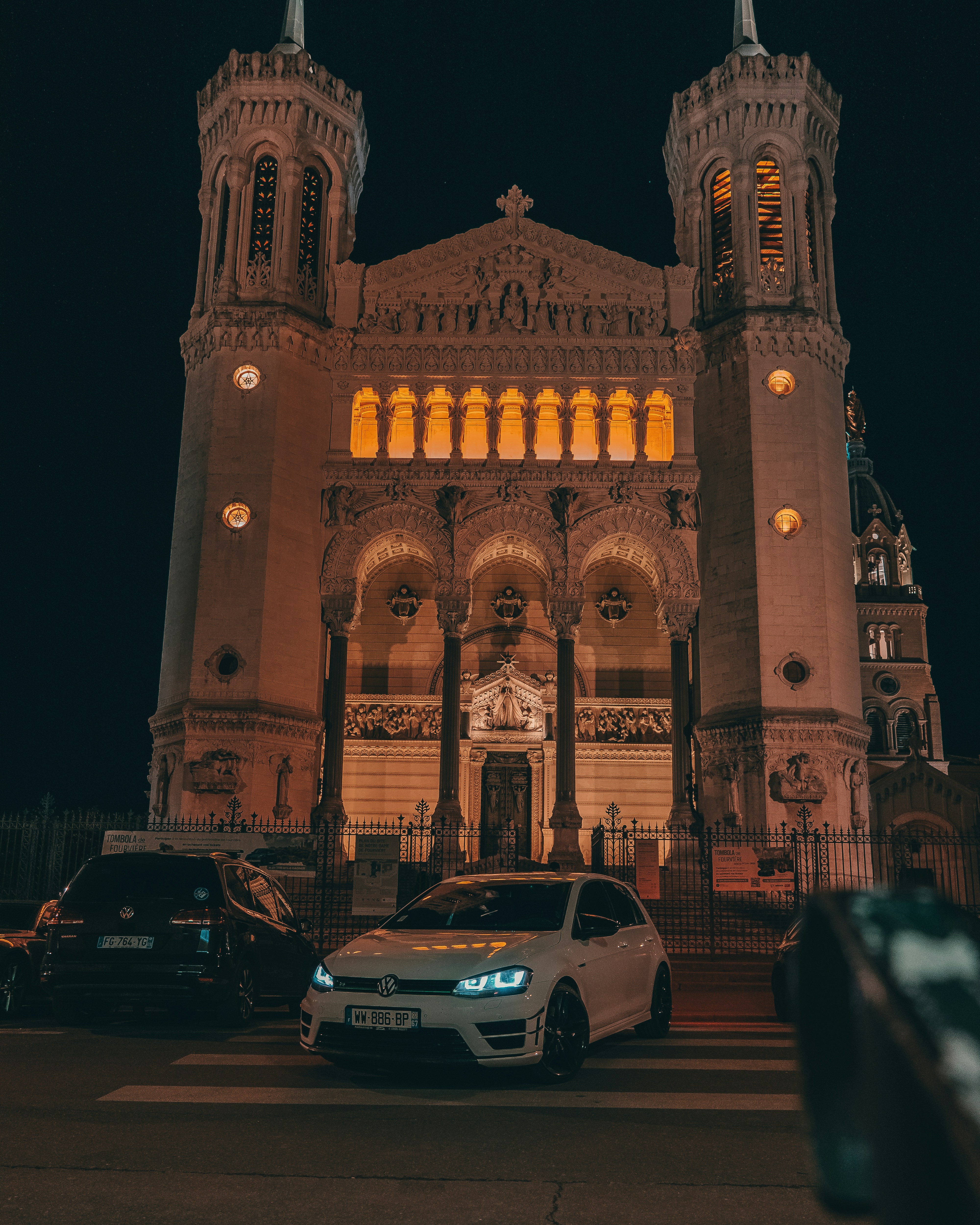 Midnight Facade: Warm Arches and the White Car Anchoring the Cathedral