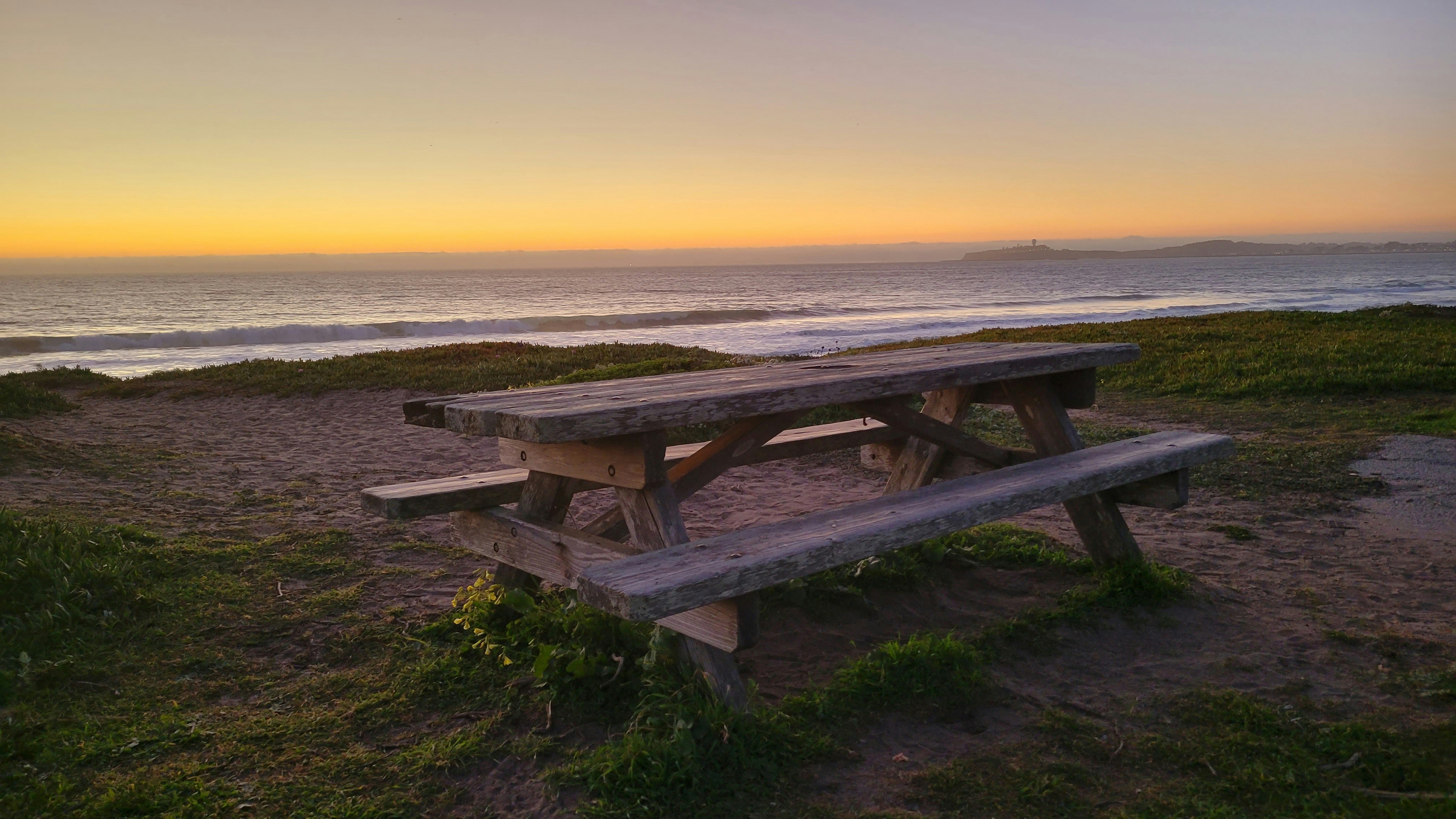 Dusk Sentinel: A Weathered Picnic Table by the Quiet Sea