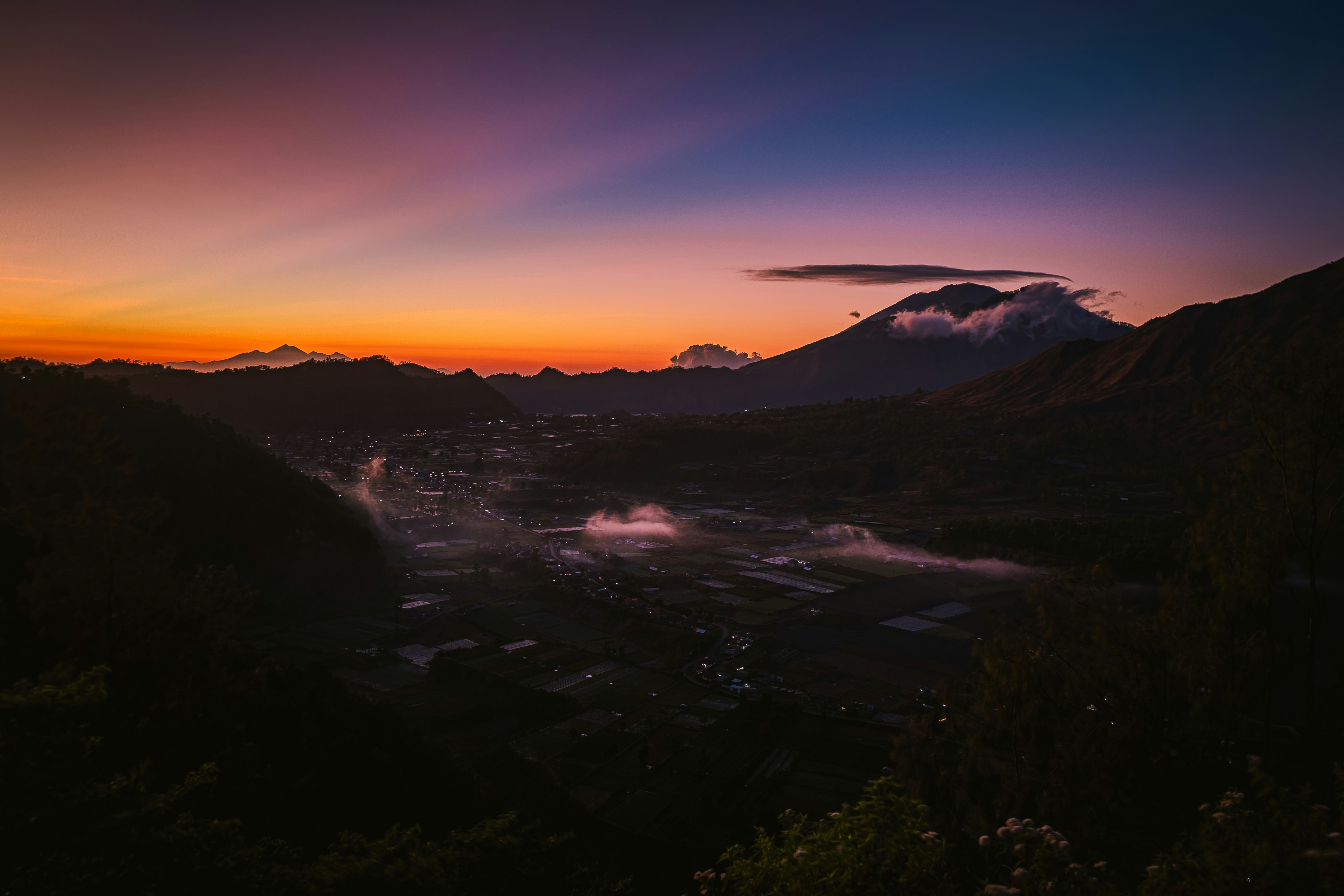 Dramatic sunrise casting vibrant hues over mist-shrouded mountains and valleys.