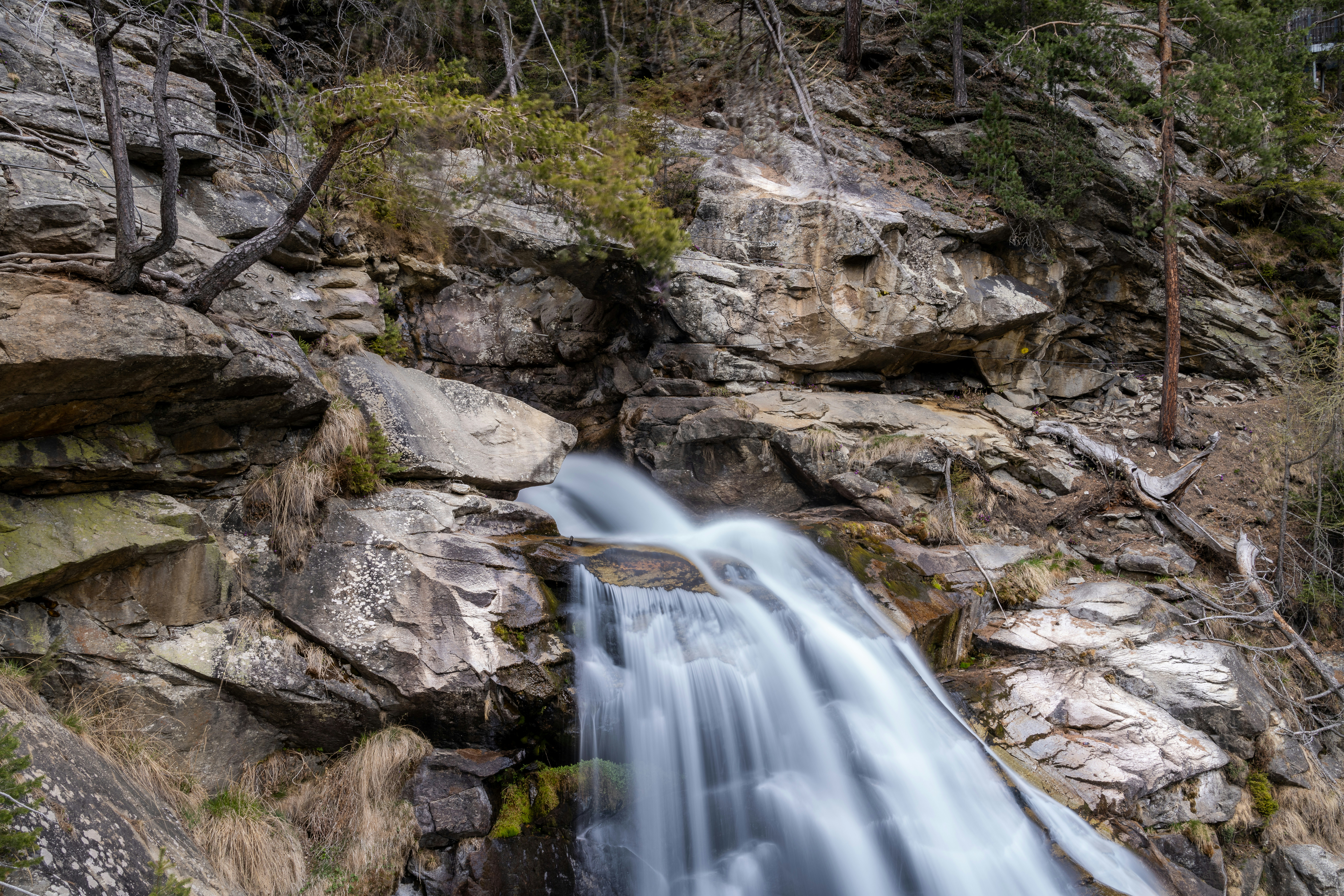 Smooth waterfall cascading over rugged rocks in a forest setting.