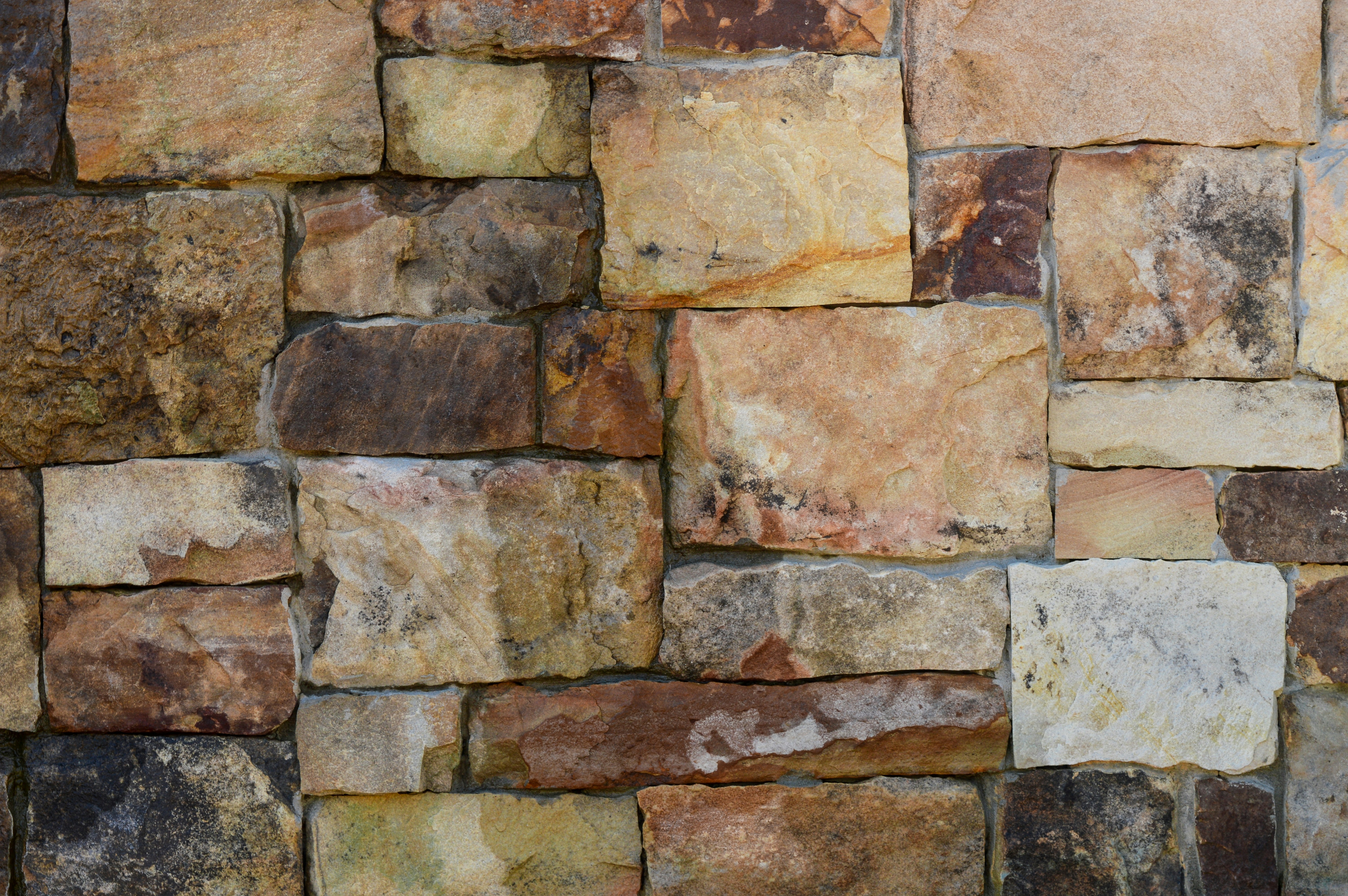 Close-up view of a textured stone wall showcasing a variety of colors and patterns in the natural stone materials.