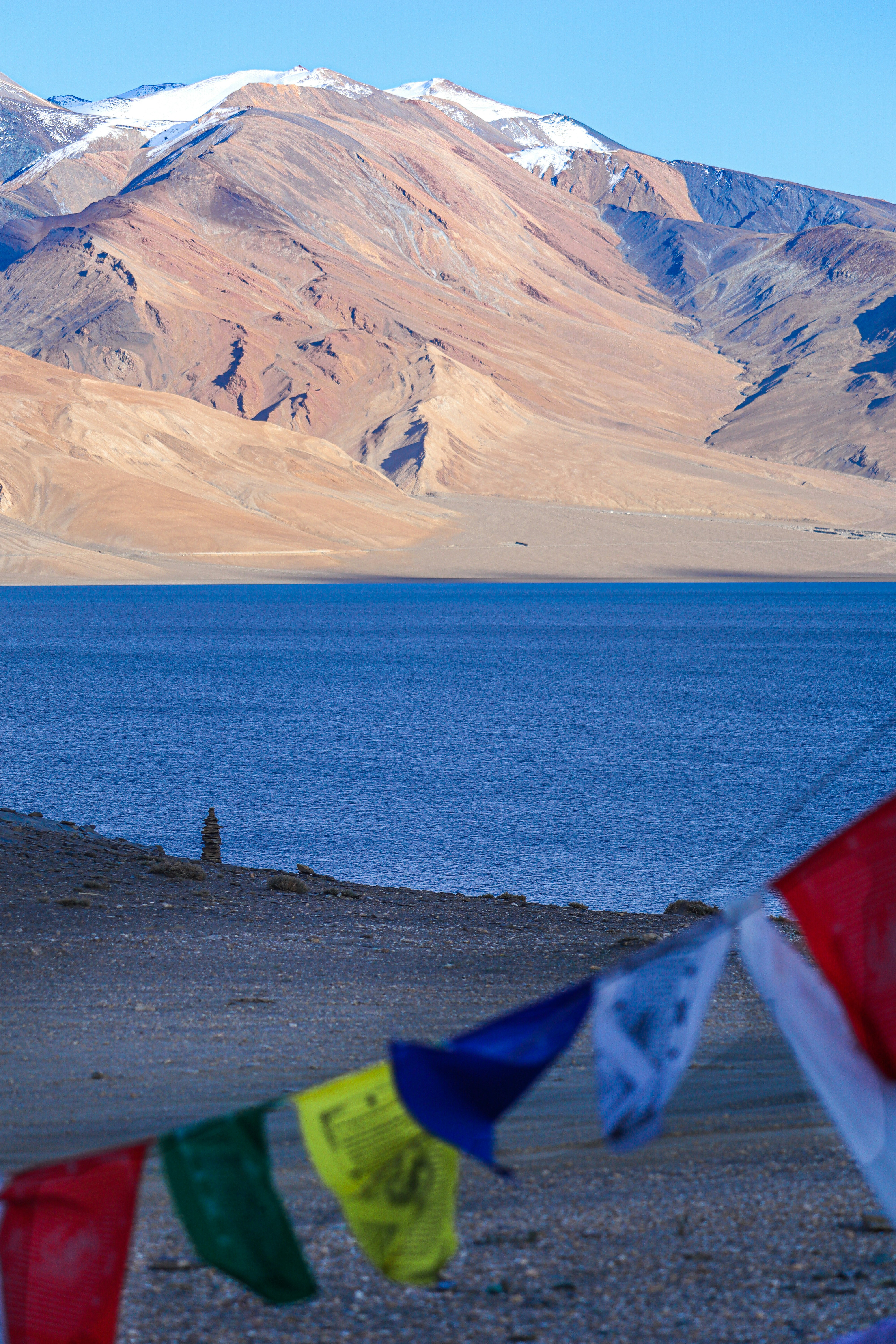 Azure Basin: Prayer Flags Framing a Lake Between Snow-Dusted Peaks