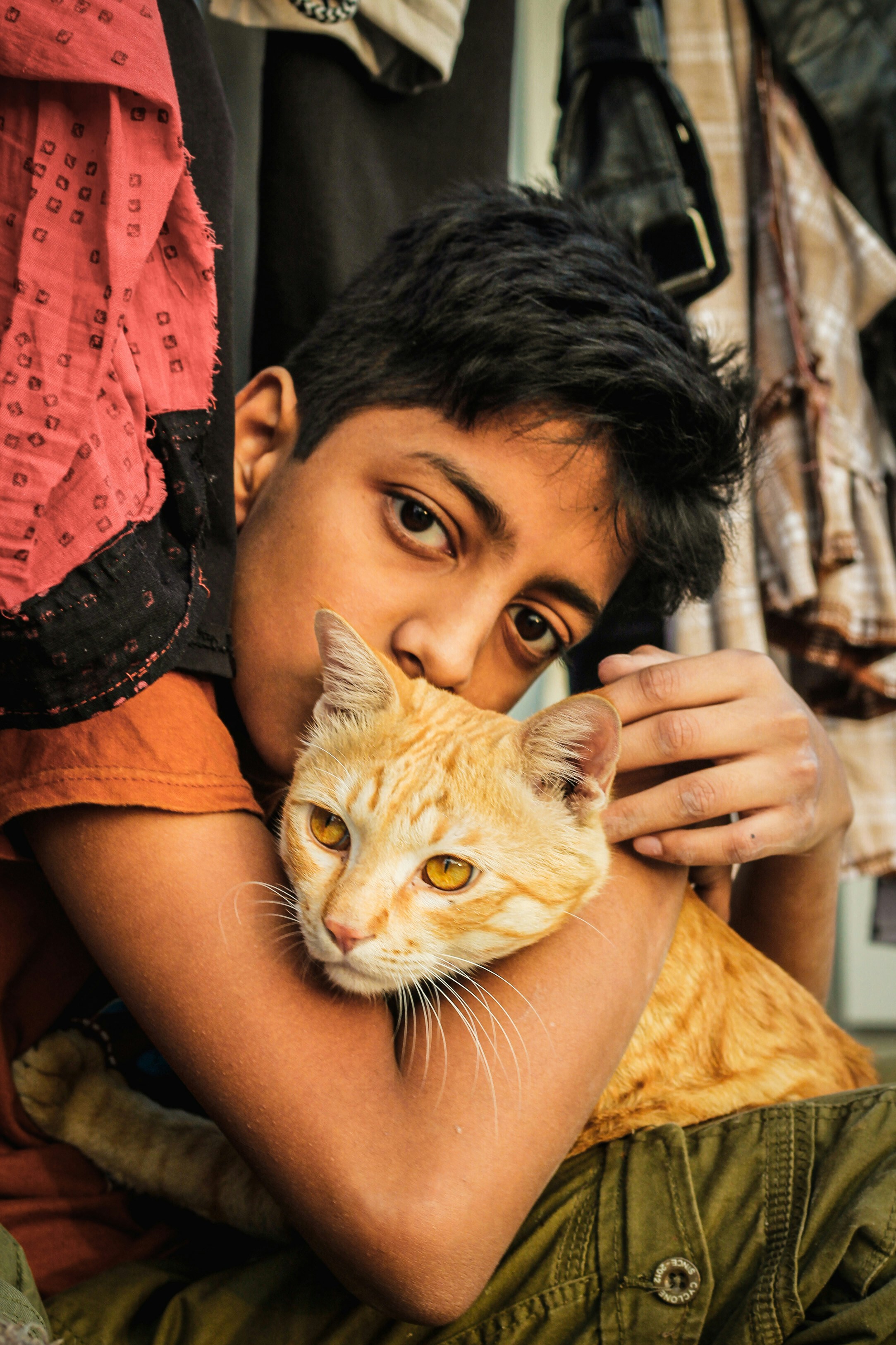 Boy and orange cat share a quiet moment in a cozy embrace