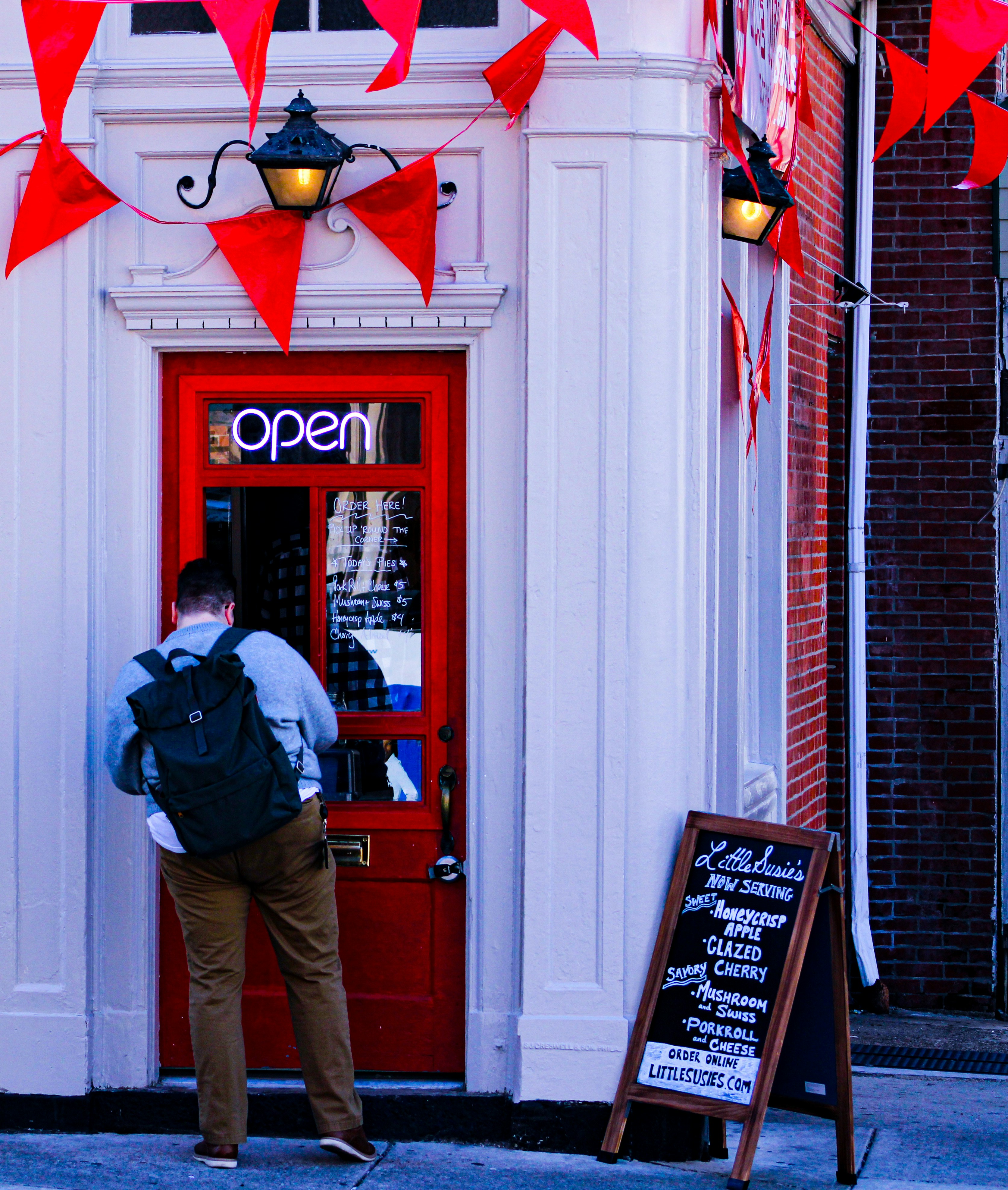 Open Door, Festive Bunting: A Backpacker Pauses at a Bright Red Shopfront