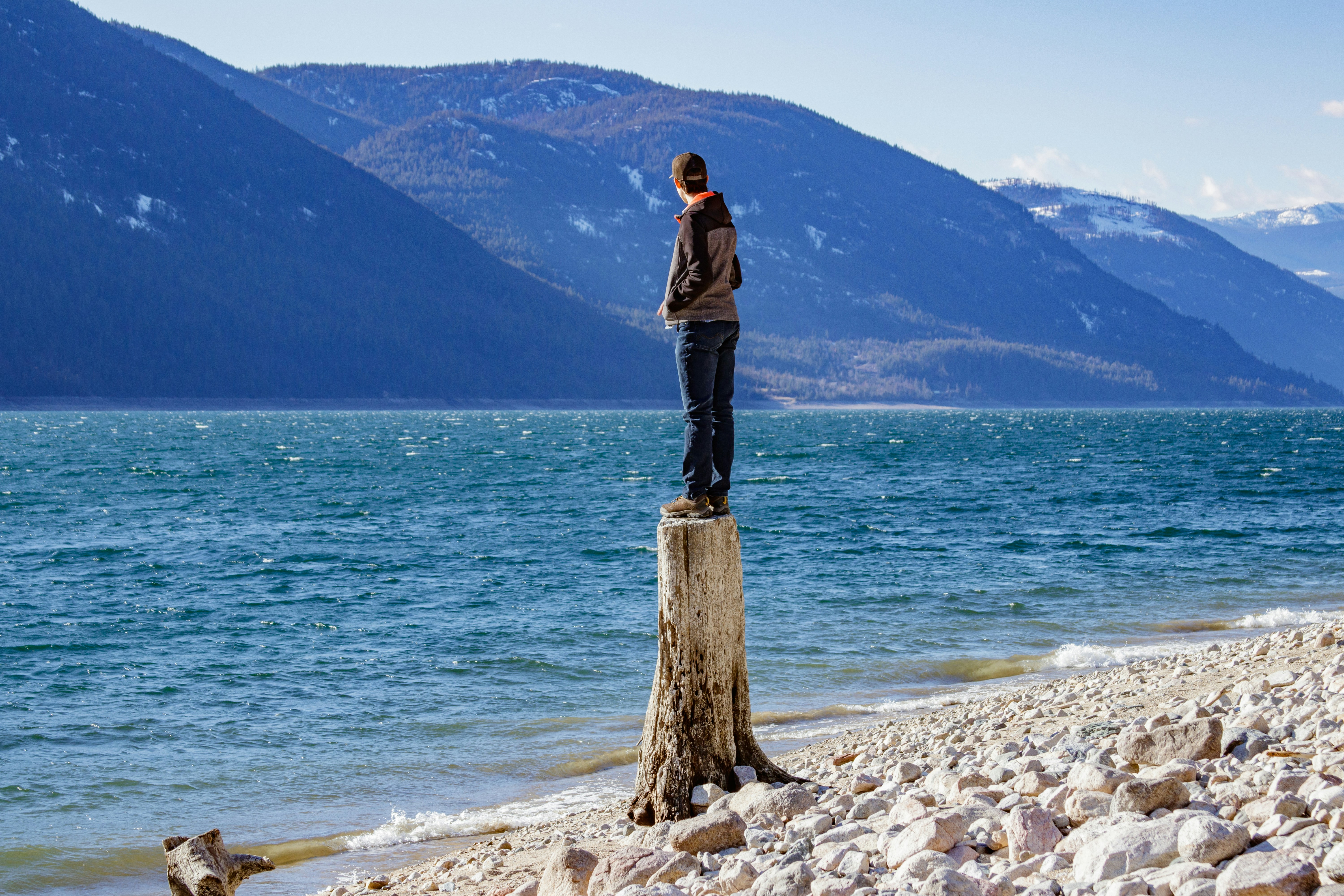 Alpine Standstill: Lone Figure on a Weathered Post Over a Glacier-Blue Lake