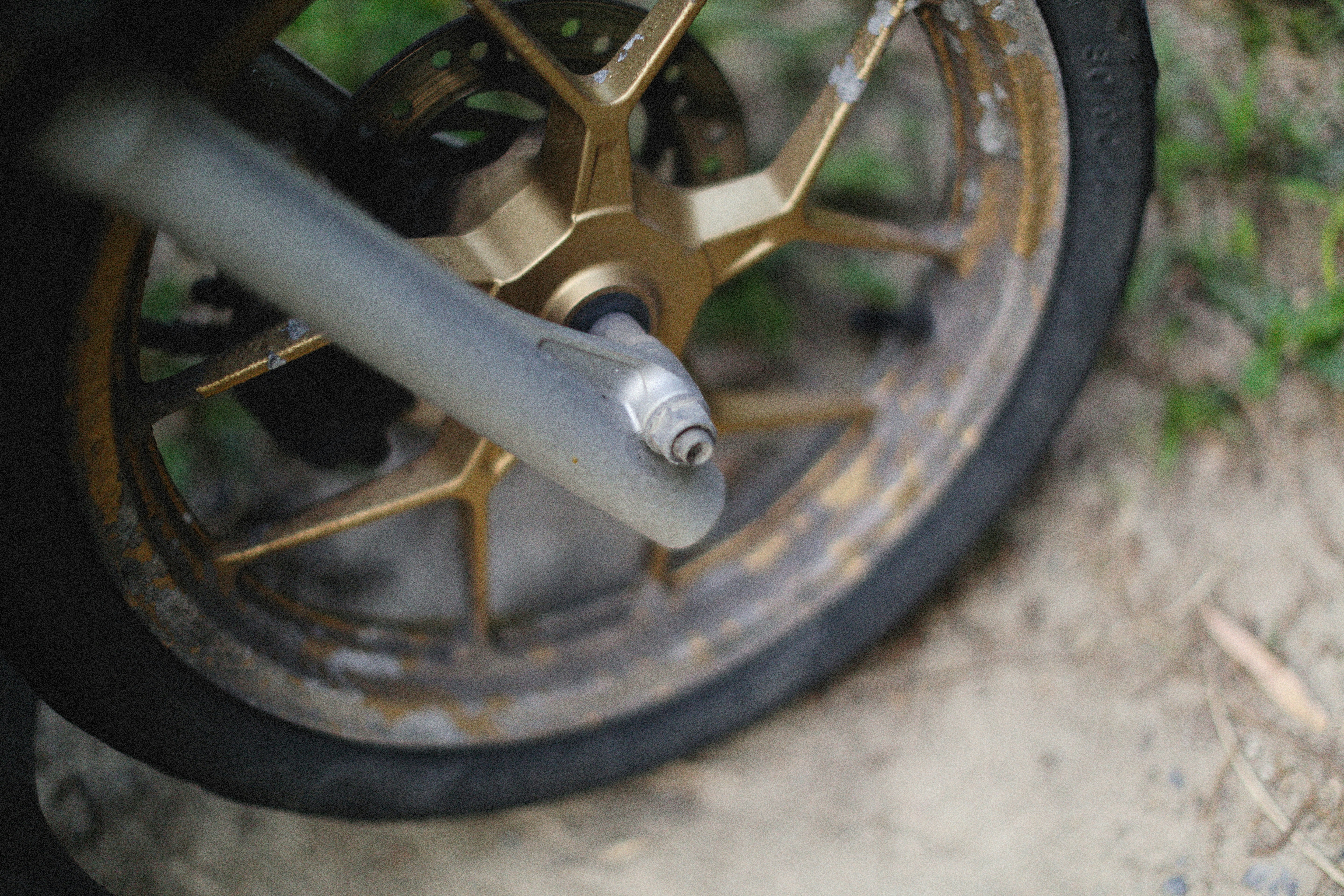 Close-up of a motorcycle wheel showcasing intricate spokes and signs of wear, emphasizing the passage of time and use.
