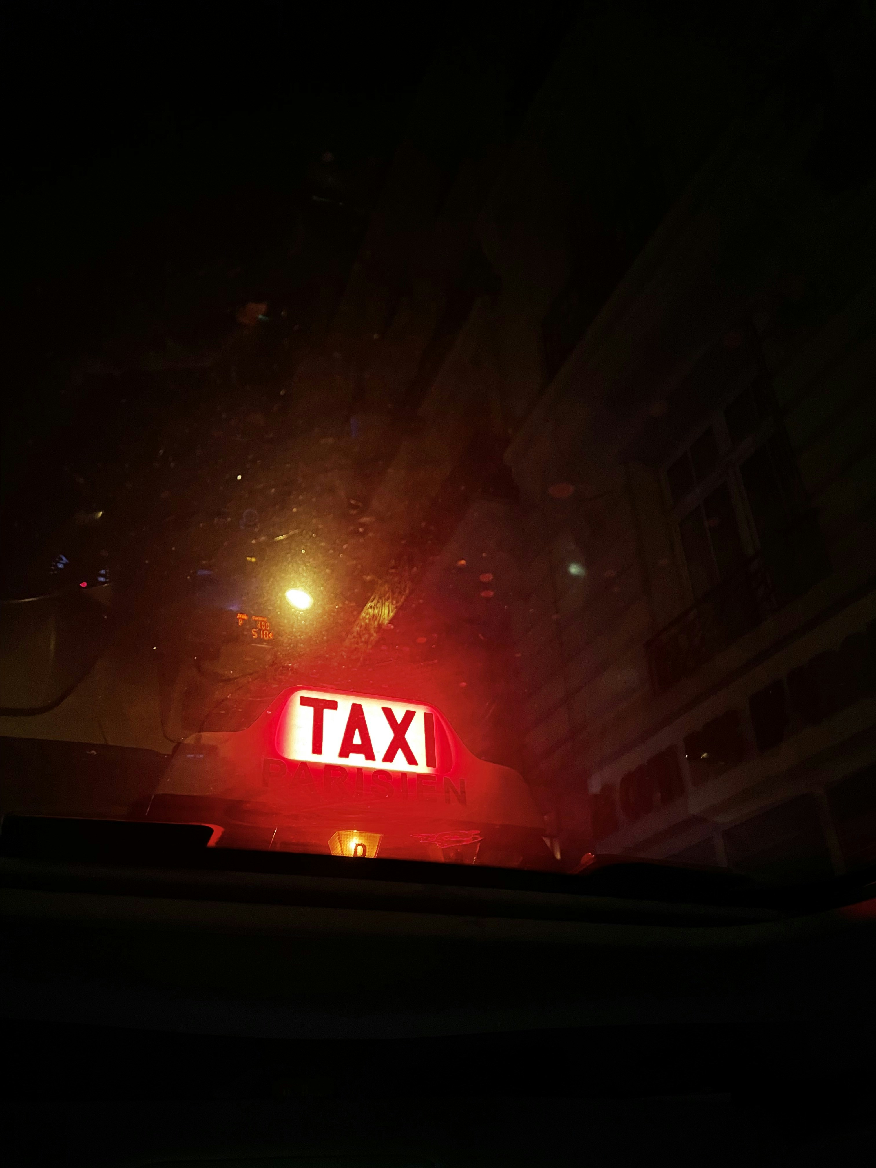 Crimson Taxi Sign Through Rainy Night Glass