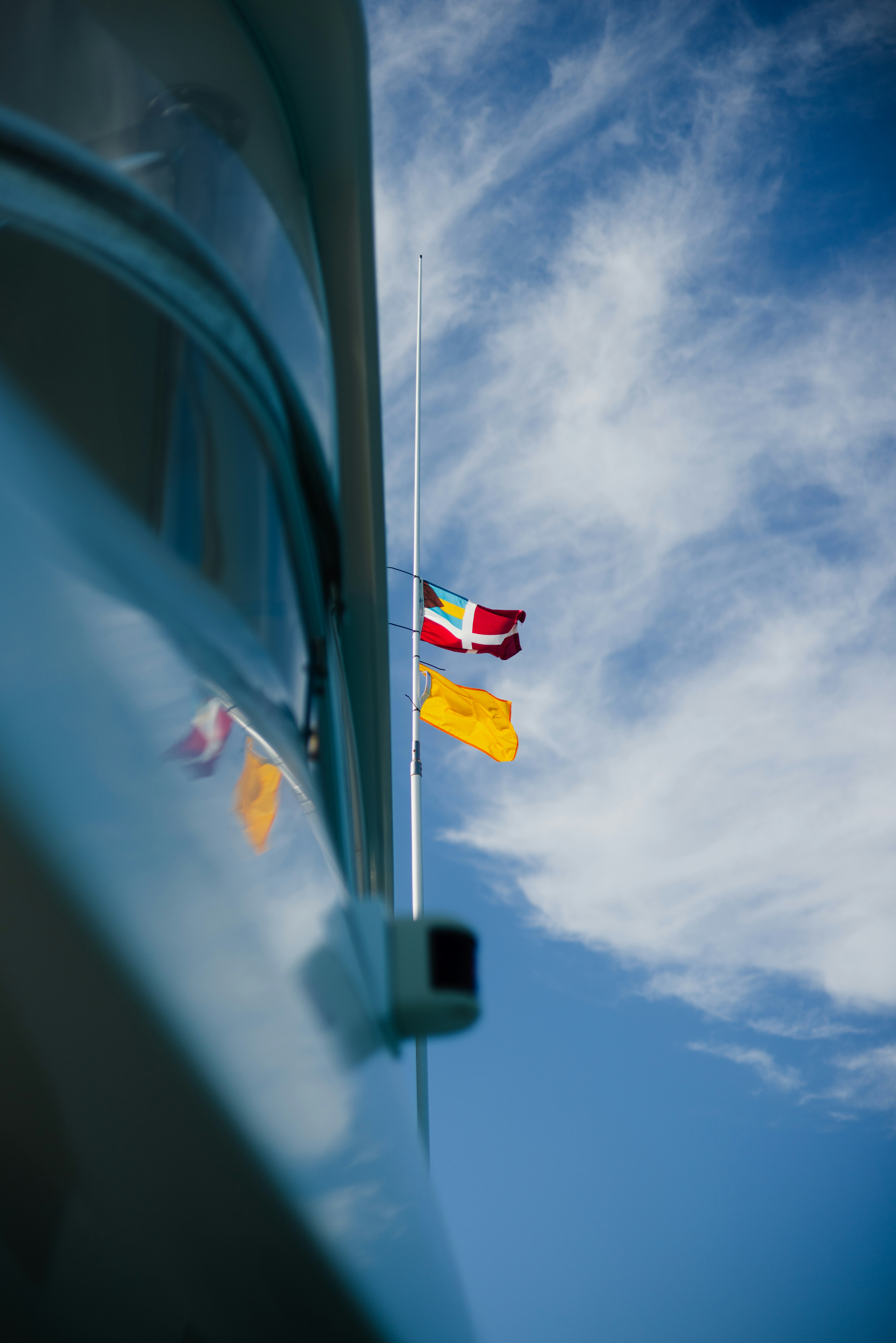 Flags at the Bow: A Tilted Vessel Under a Blue Sky