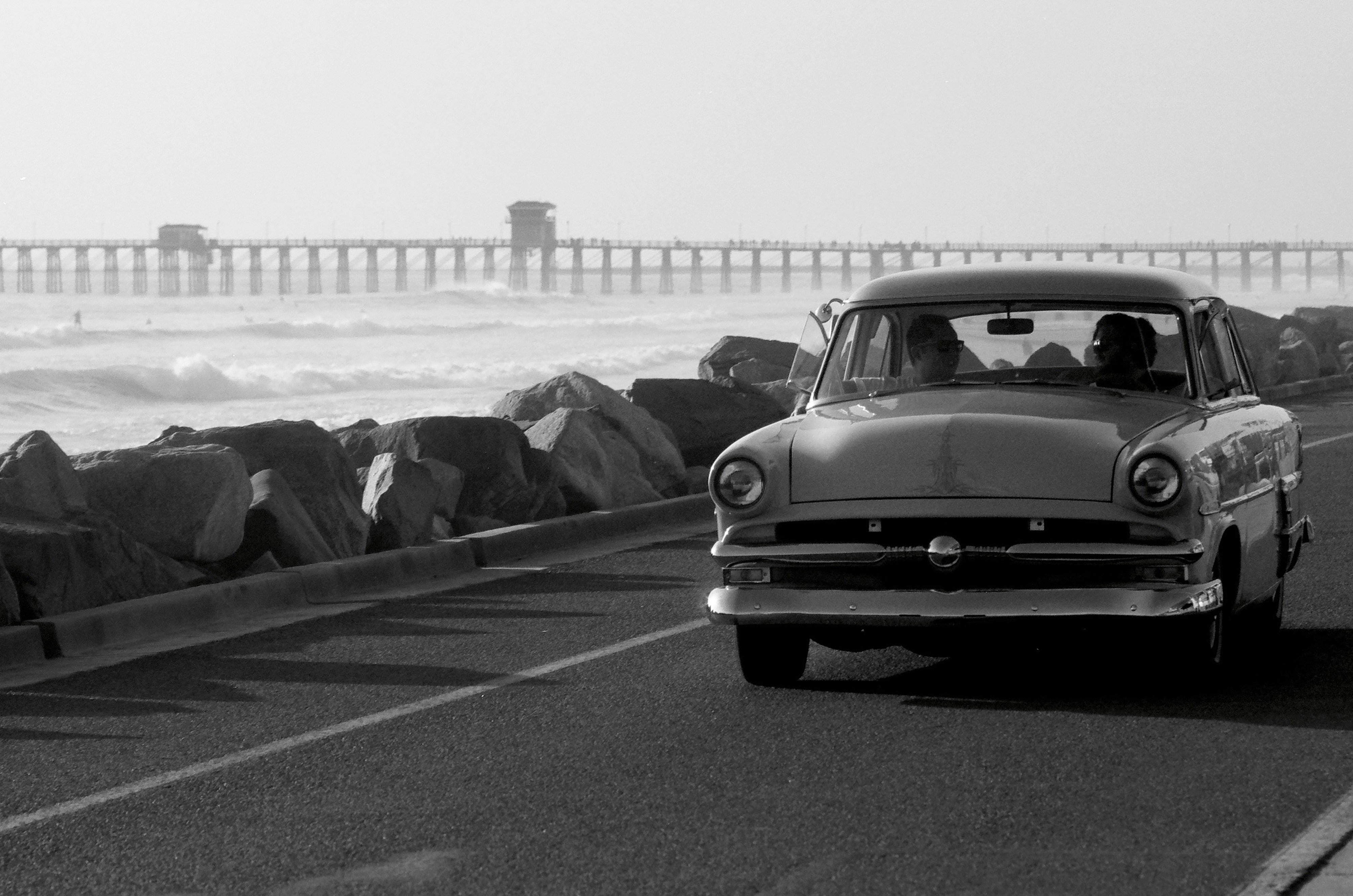 A car driving on a road with rocks on the side photo – Free Grey Image ...