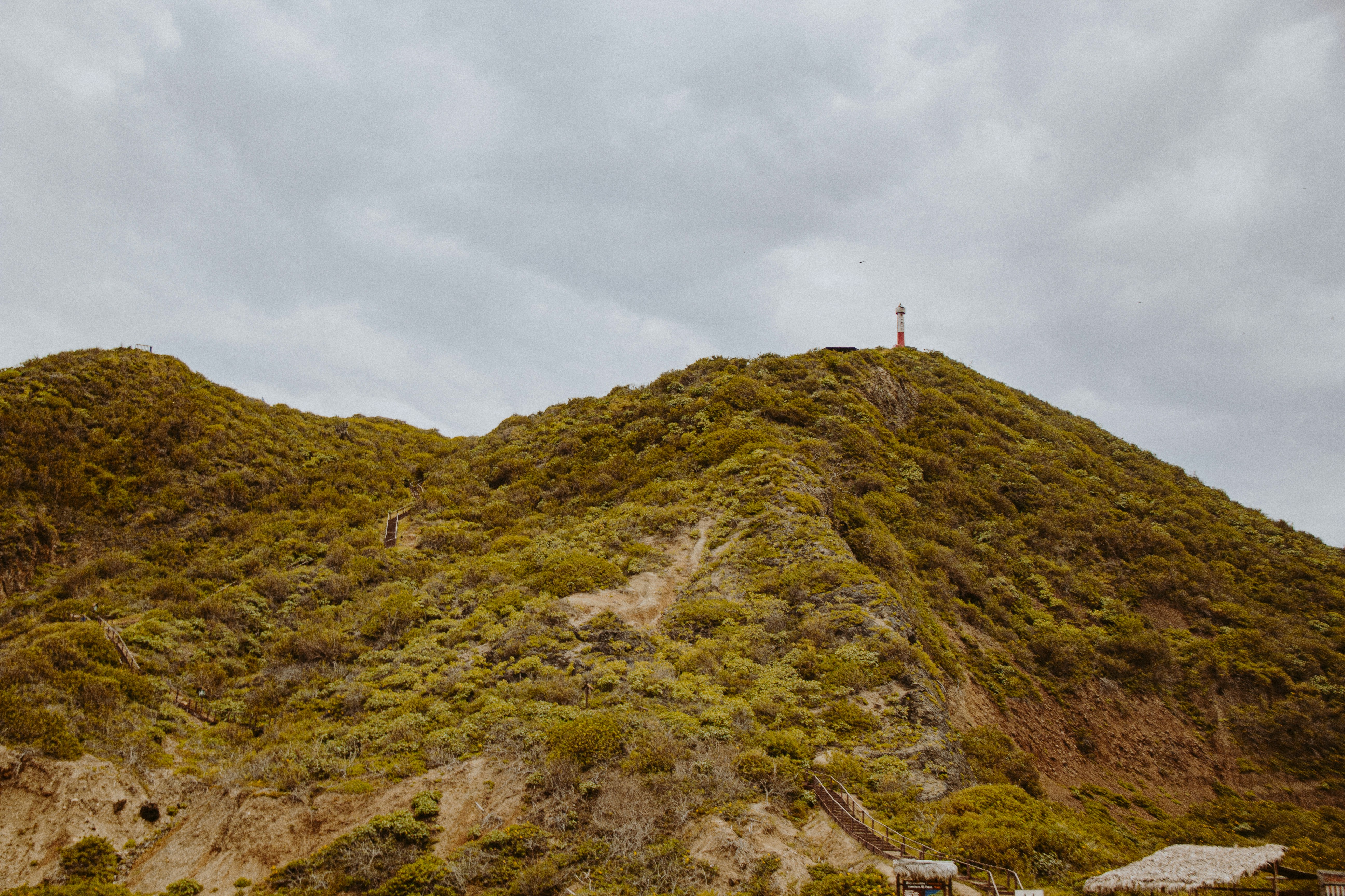 Lone Antenna Crowned Hilltop Under Overcast Sky