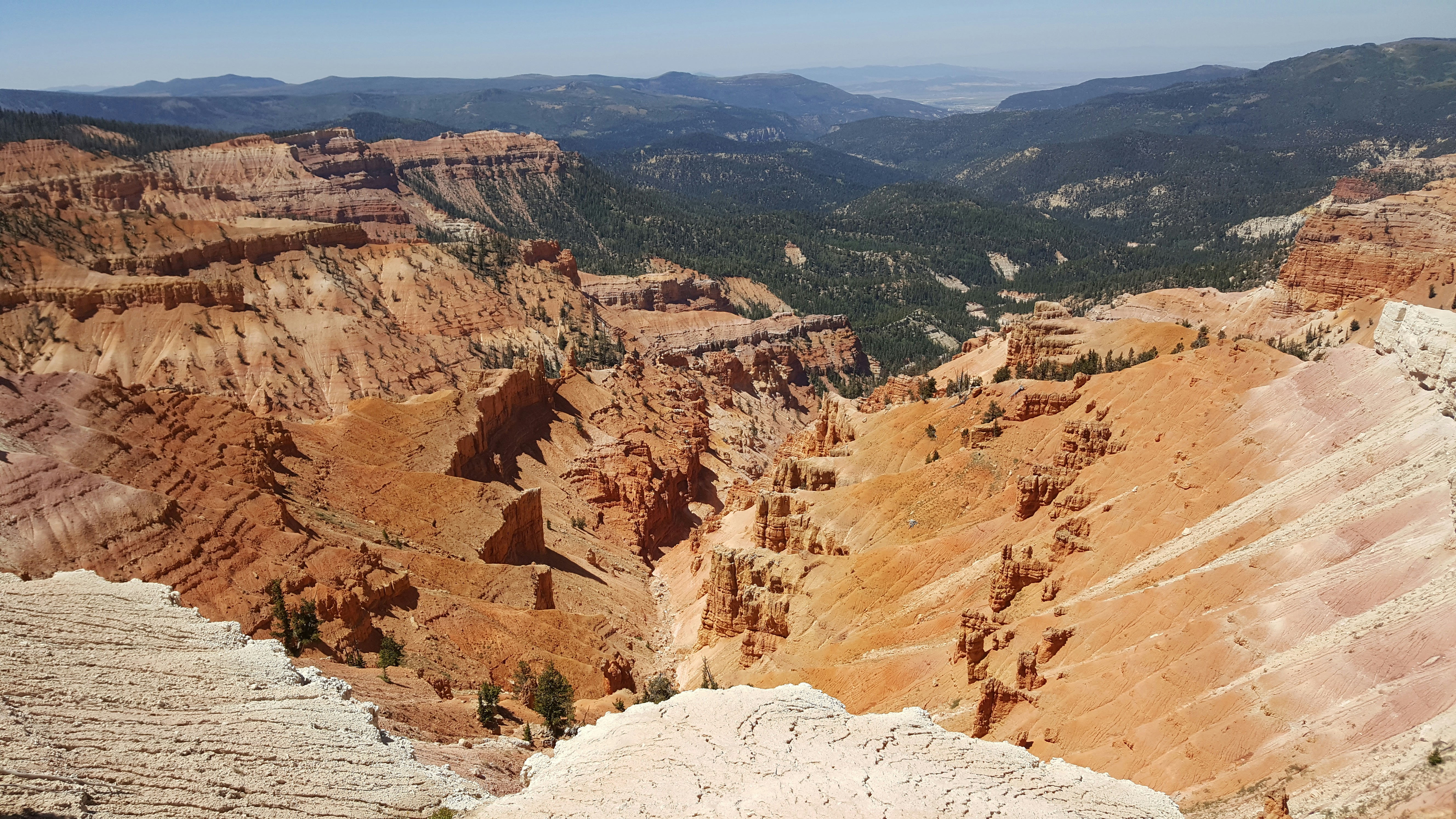 Vast canyon landscape showcasing layered rock formations and vibrant colors under a clear blue sky.