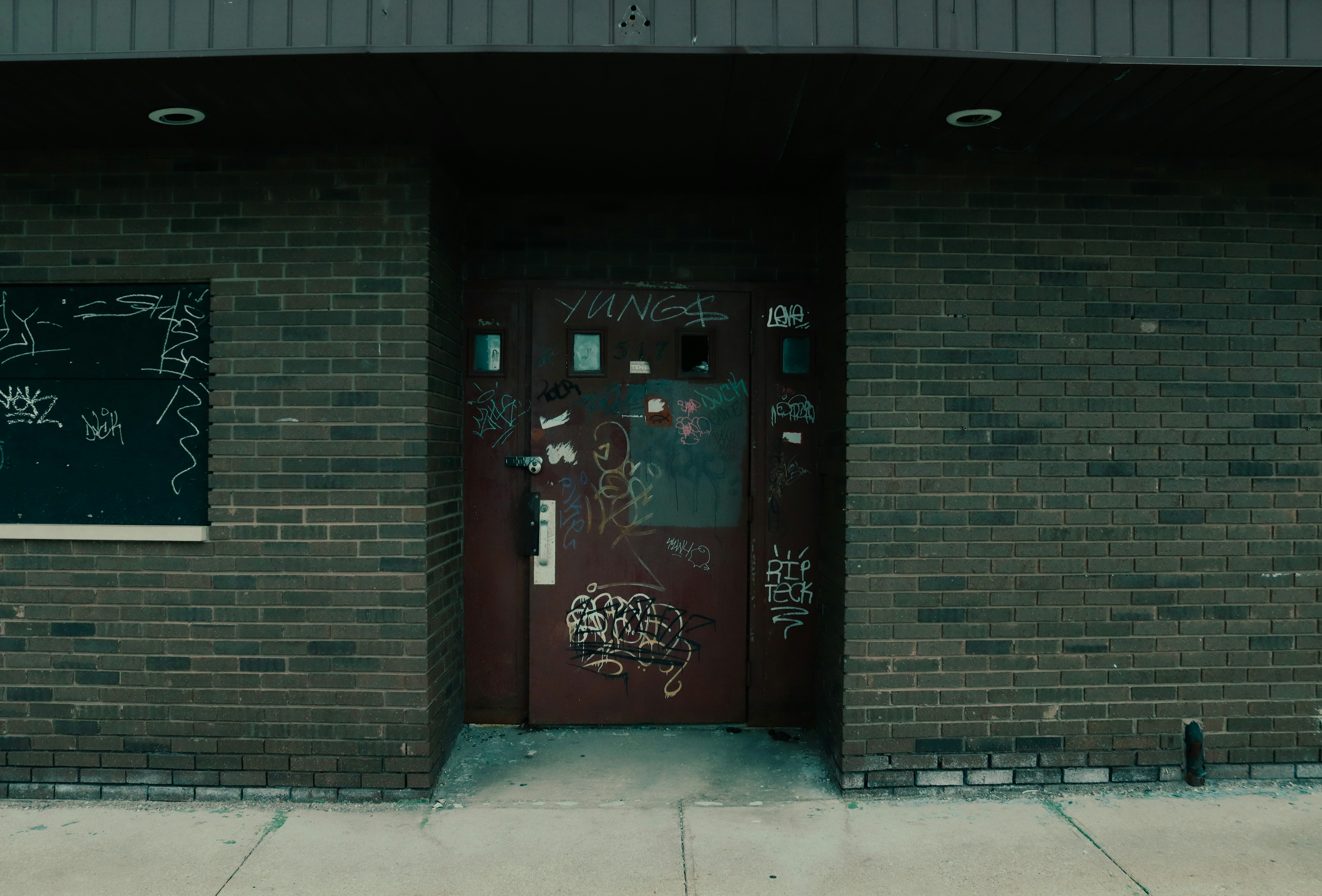 Graffitied Doorway in a Dim Brick Facade