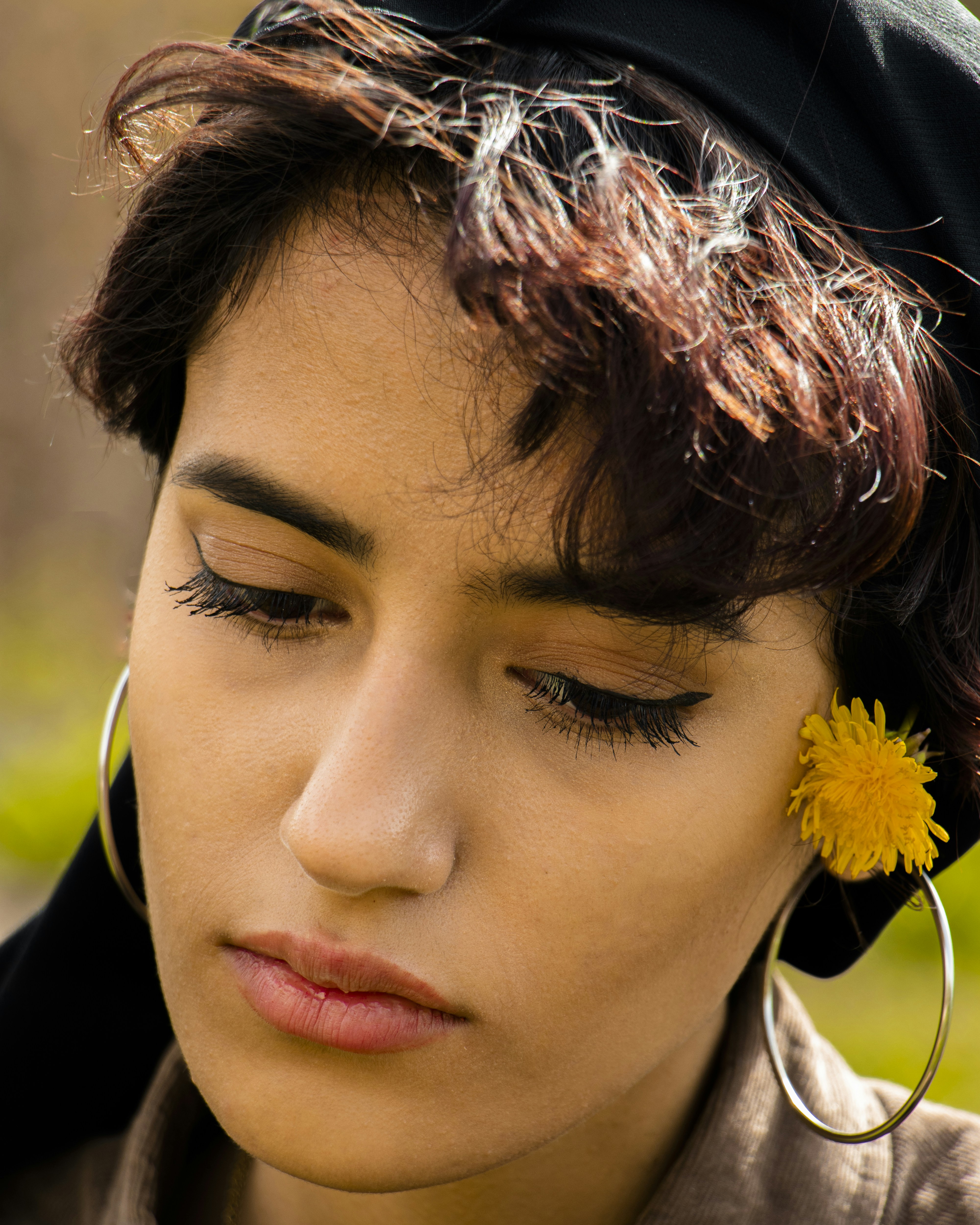 Close‑up of a woman with a yellow flower in her hair, eyes closed and soft sunlight