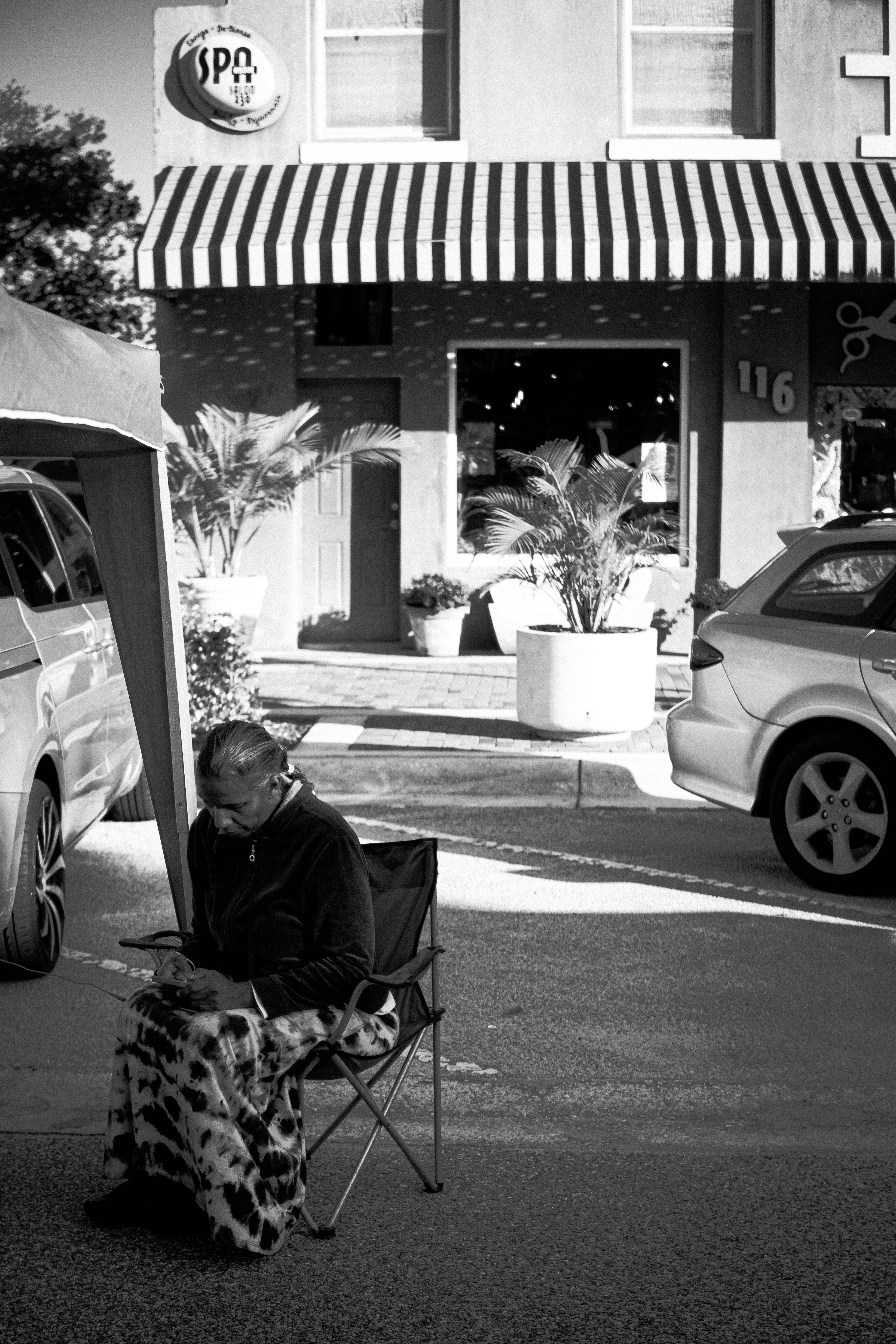 Une personne assise sur une chaise à l’extérieur d’un magasin photo ...