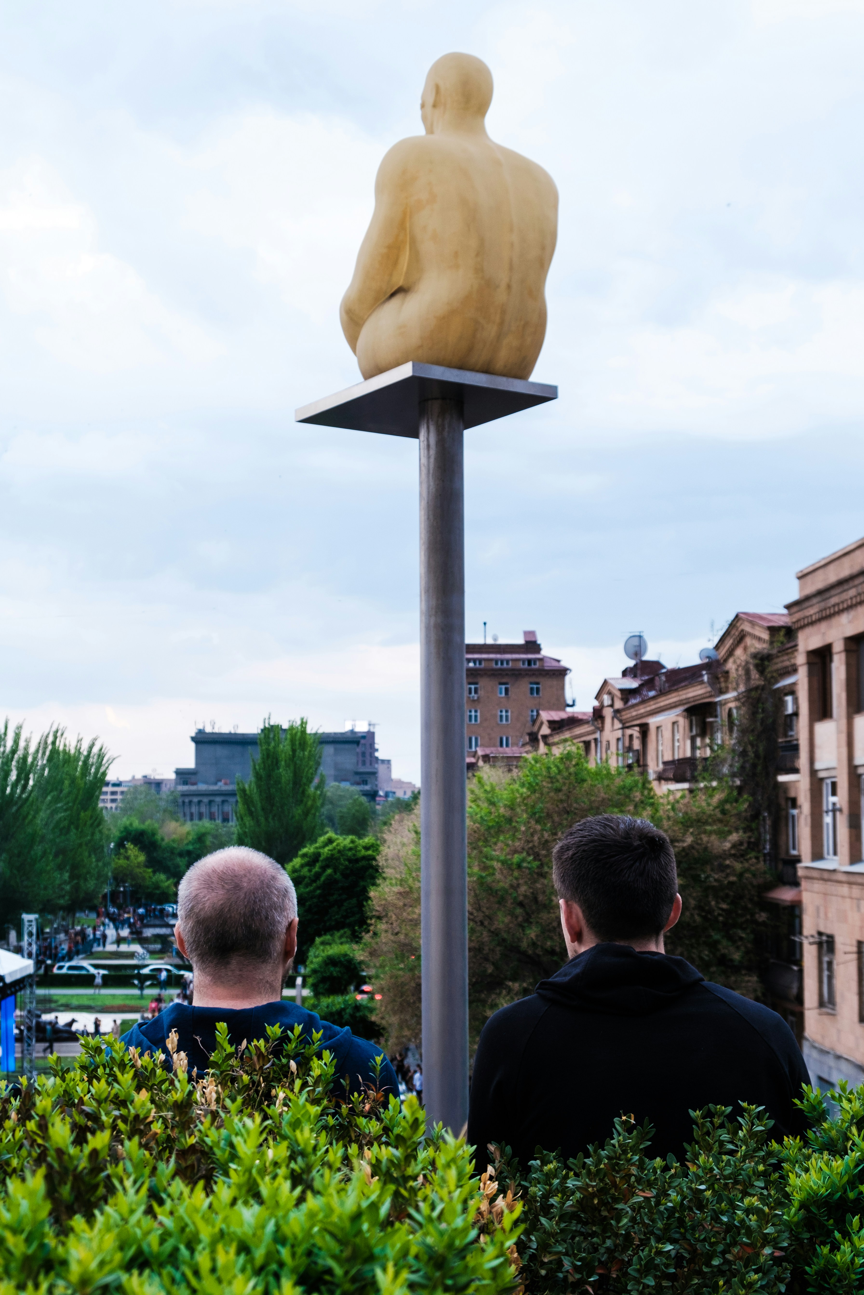 Un couple d’hommes regardant une statue d’un homme sur un poteau photo ...