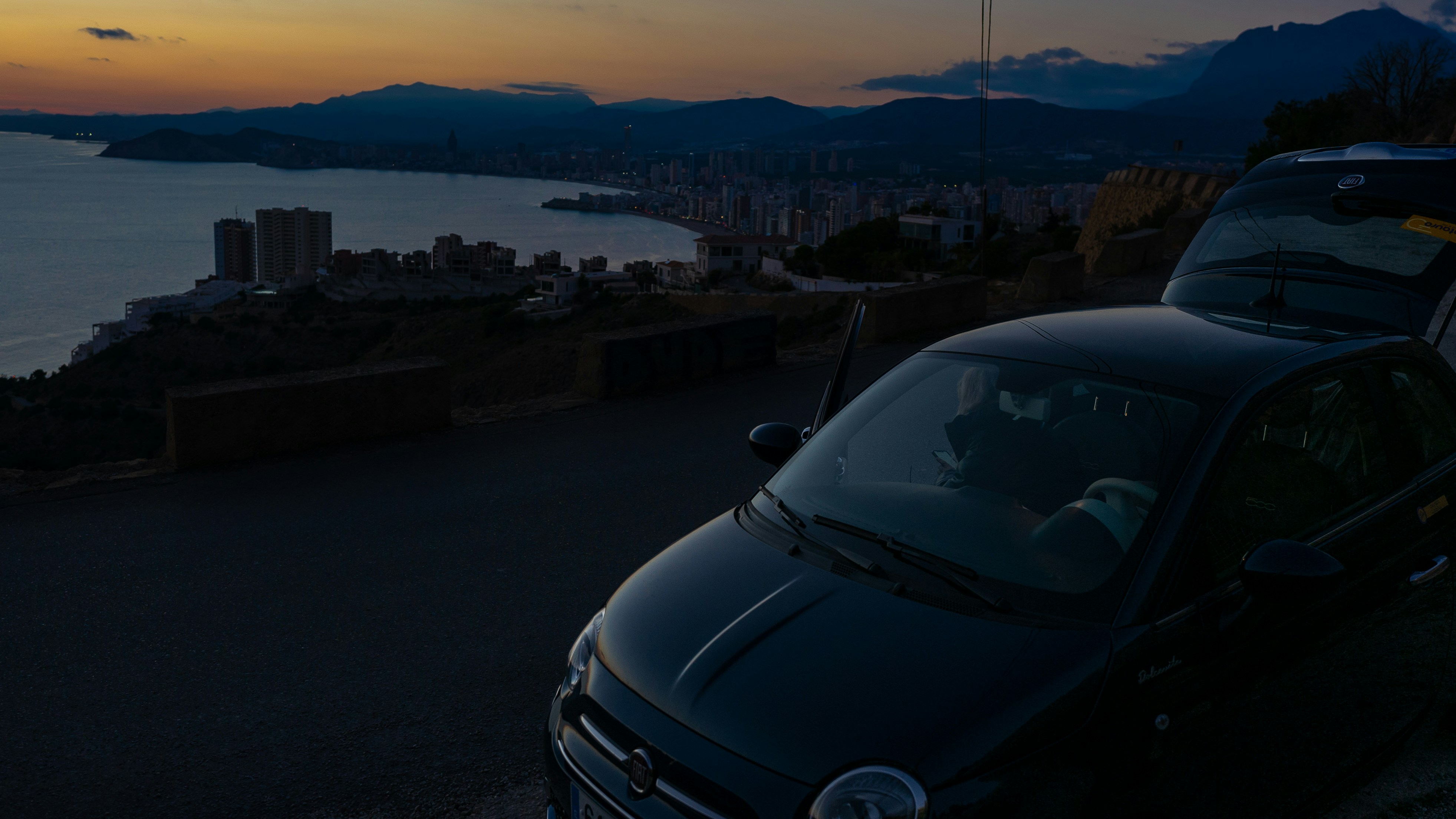 Dusk Over the Bay: An SUV Paused on the Coastal Promontory
