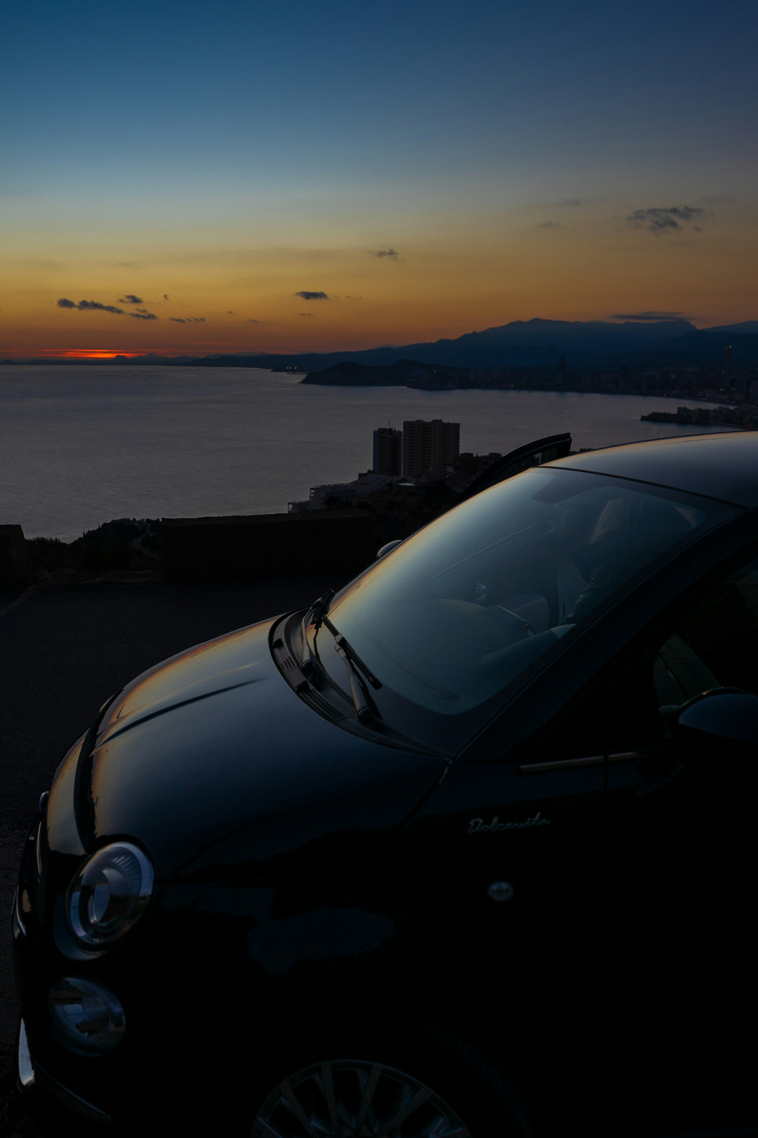 Dusk at the Bay: Sunset Silhouette Meets a Quiet Foreground Car