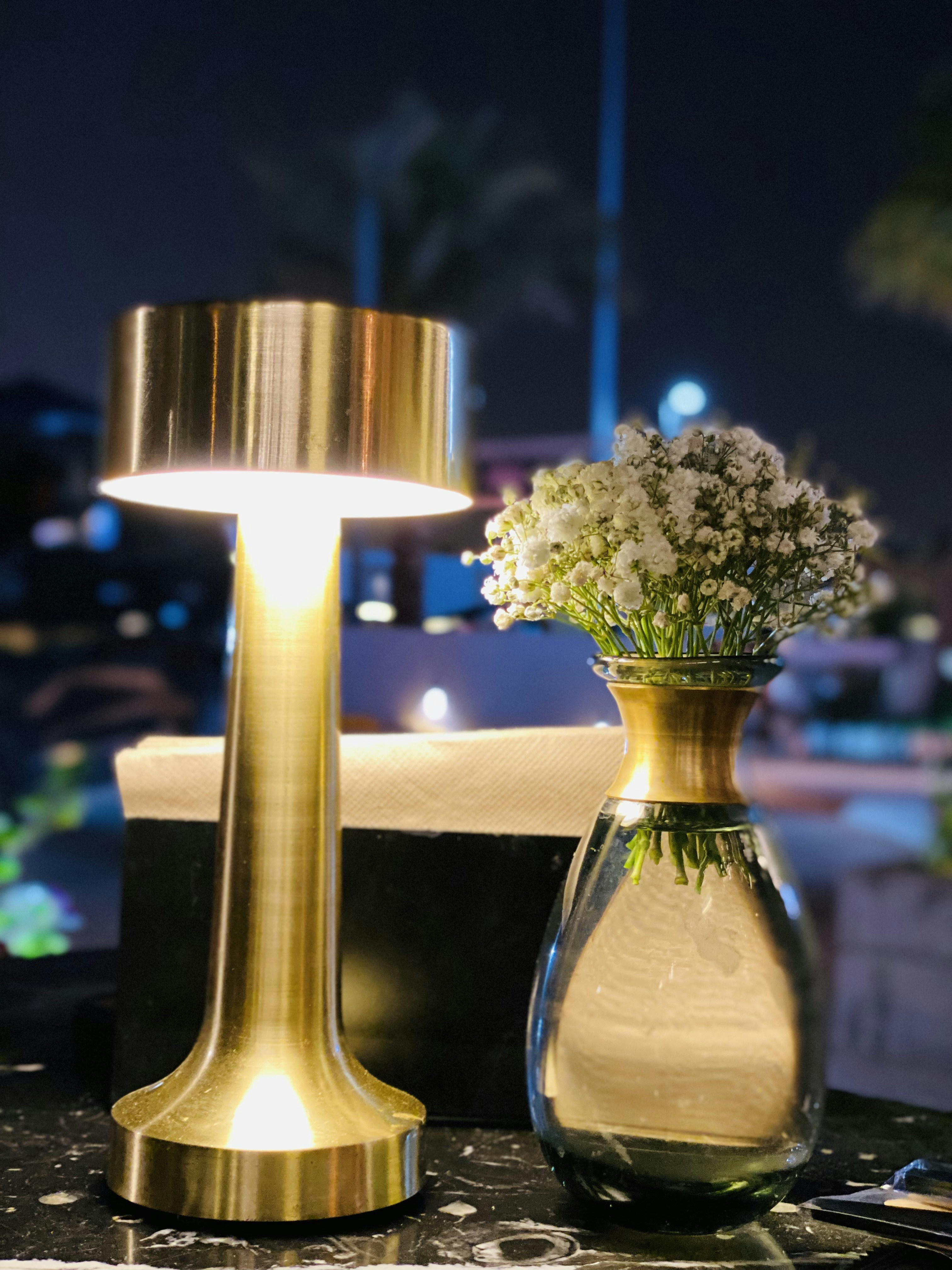 Lamplight and Bloom: Brass Table Lamp Illuminates a Glass Vase of White Baby's Breath