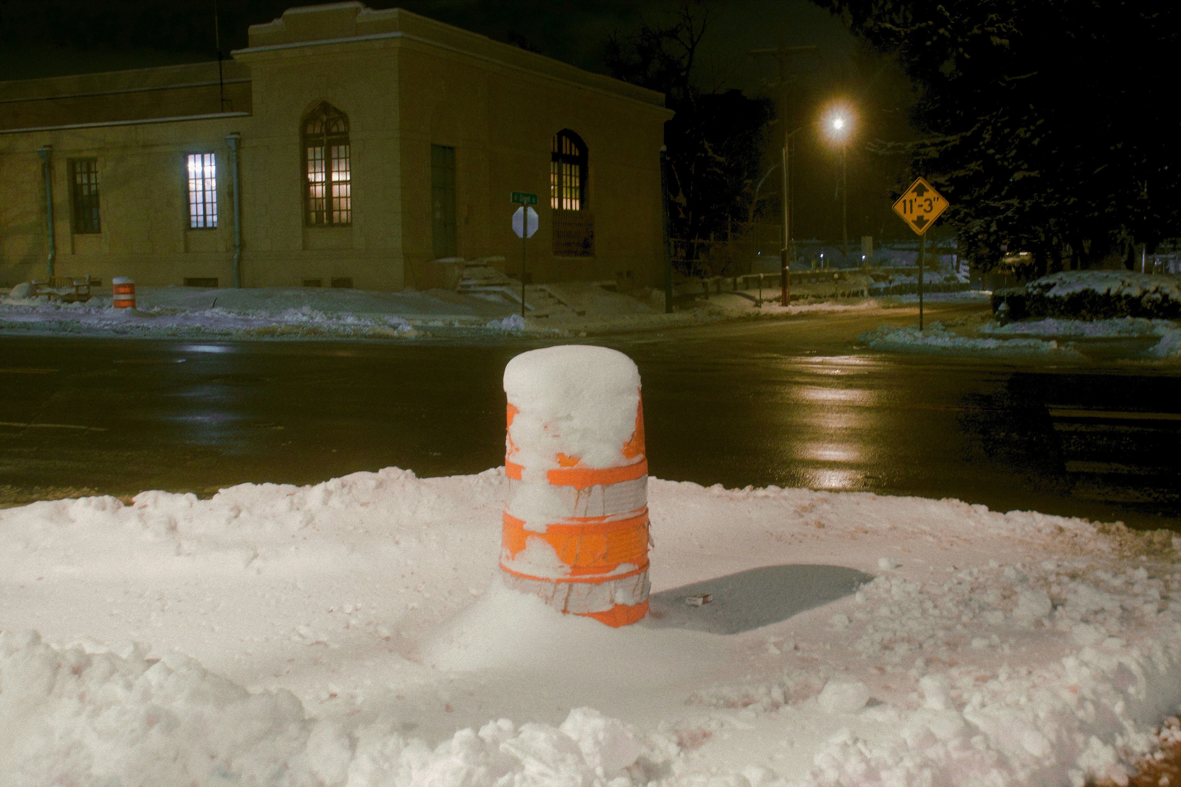Snowdrift Sentinel: A Tire-Bucket Marker Stands Guard at Night