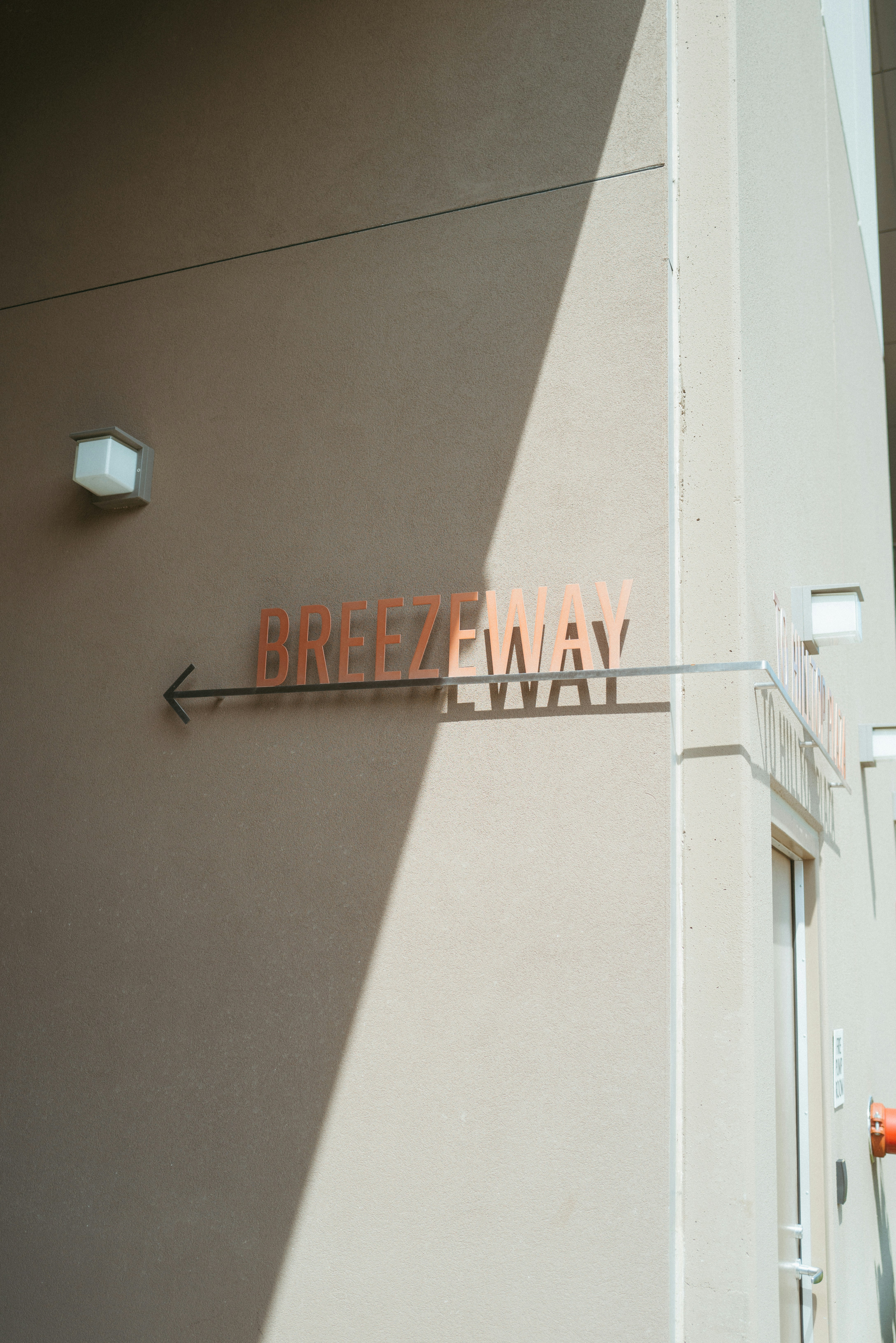 Copper Breezeway Sign Bathed in Light Under a Sharp Diagonal Shadow