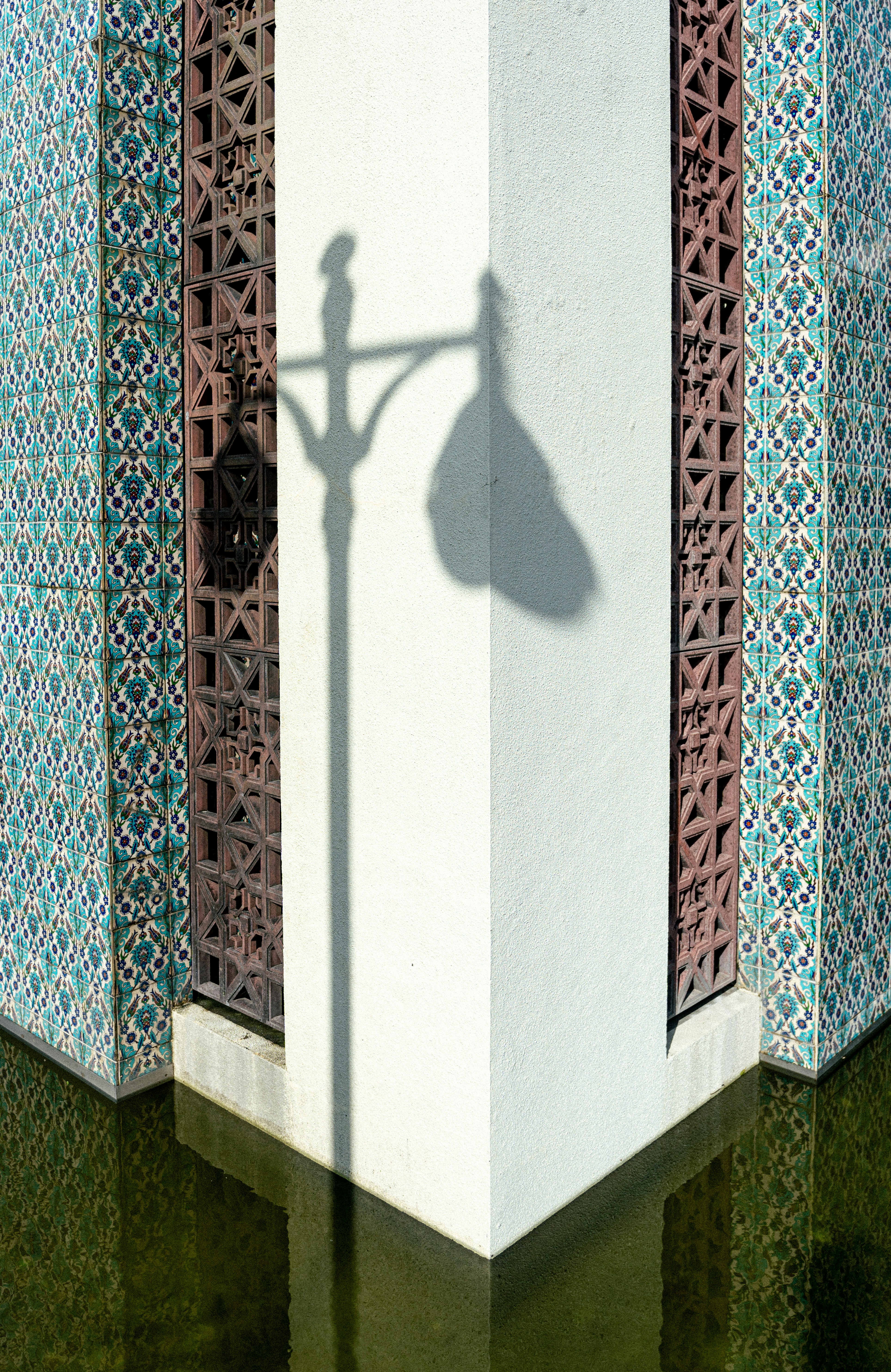 Lantern Shadow on a White Pillar Between Turquoise Tiles