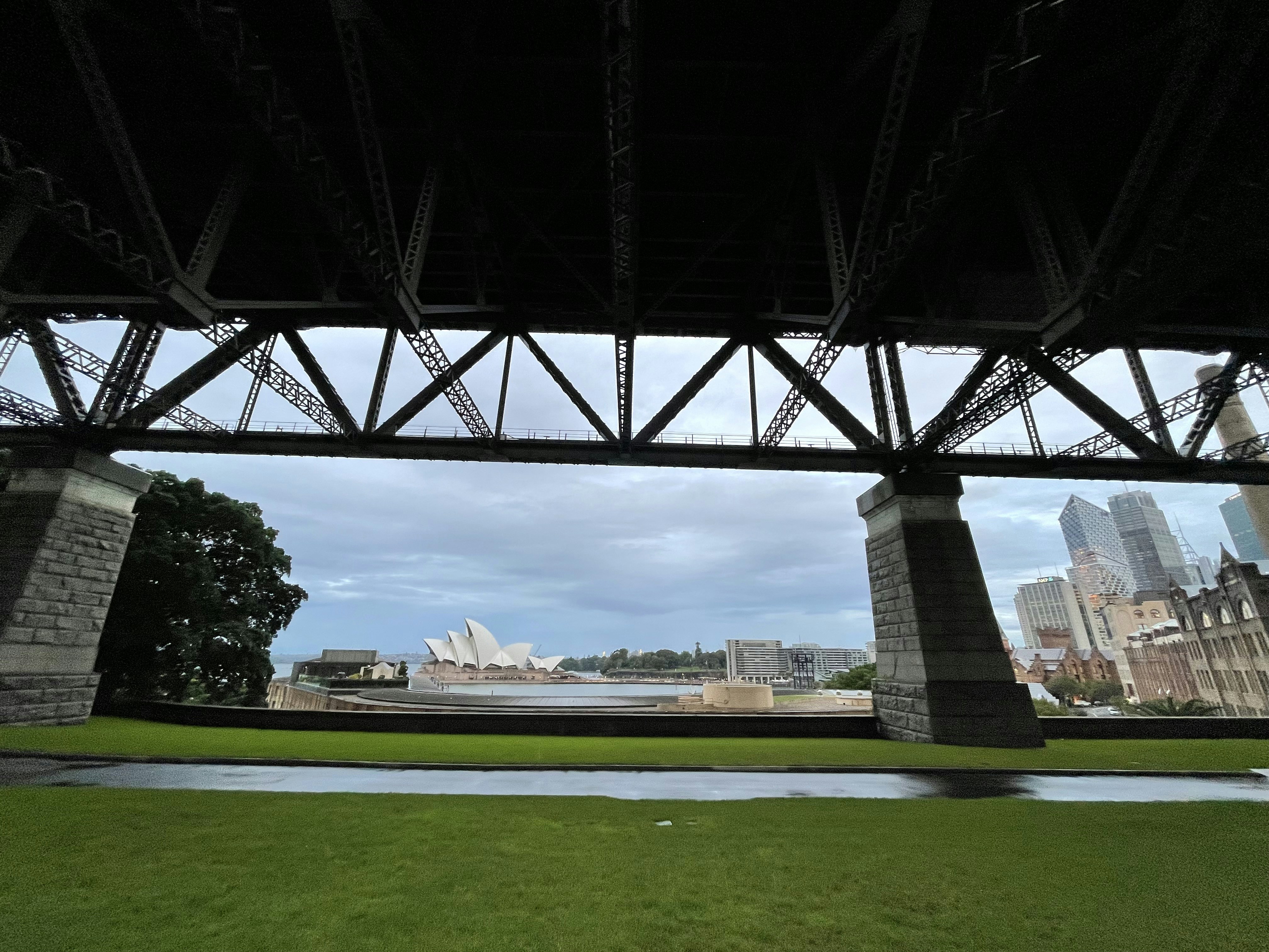 View of the Sydney Opera House framed by the structure of the Harbour Bridge, showcasing a blend of nature and urban architecture.