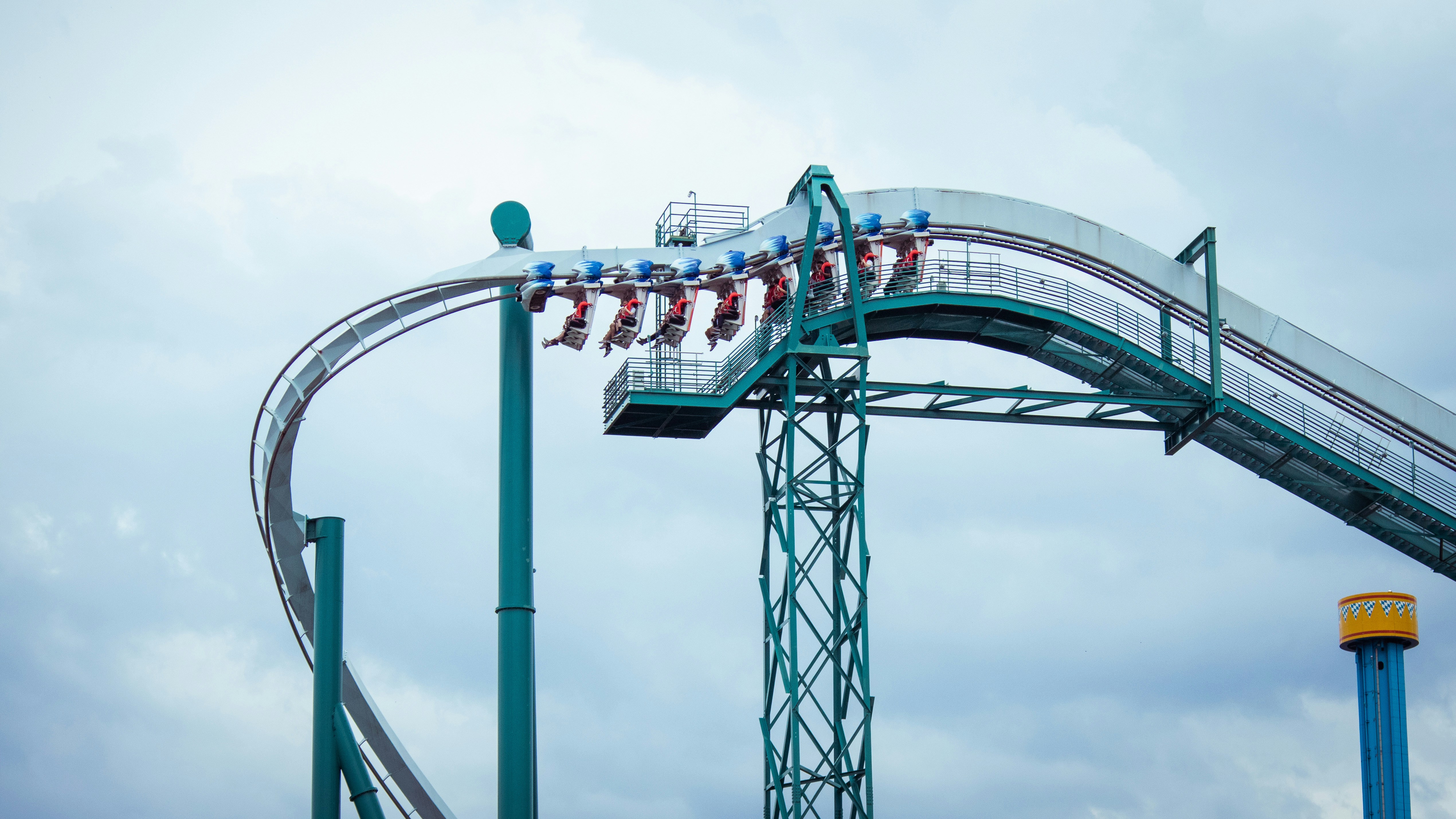 Looping Teal: Riders Crest the Curve on a Skyward Coaster