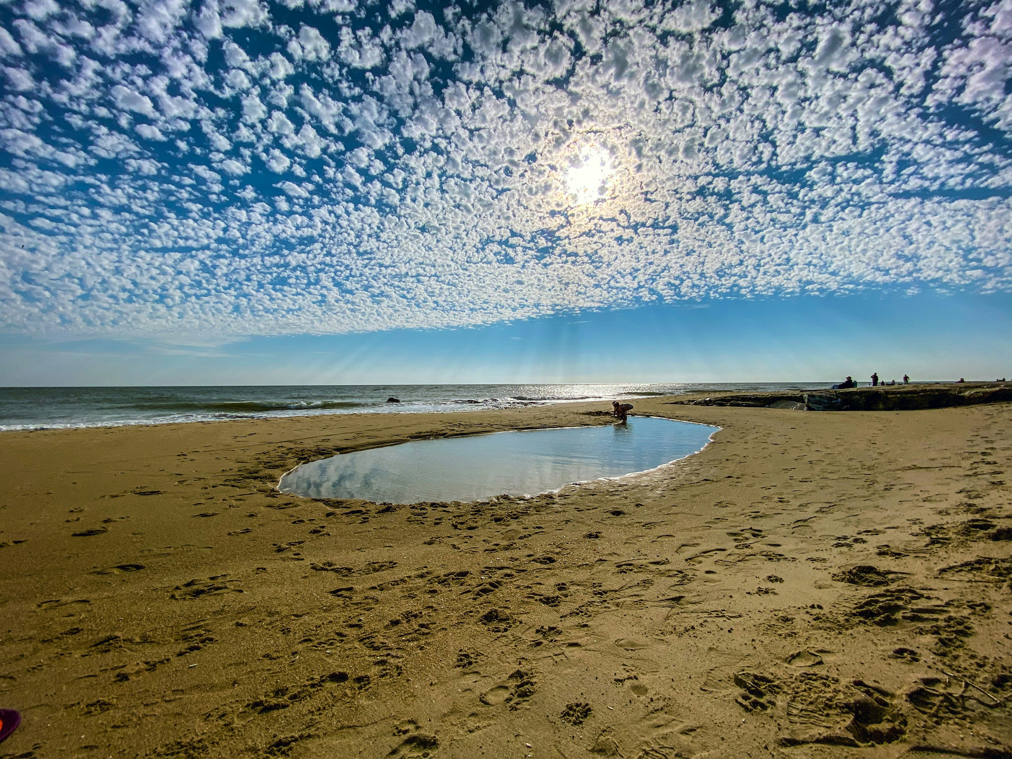 Crescent Pool on a Quiet Shore Under a Sky of Dotted Clouds