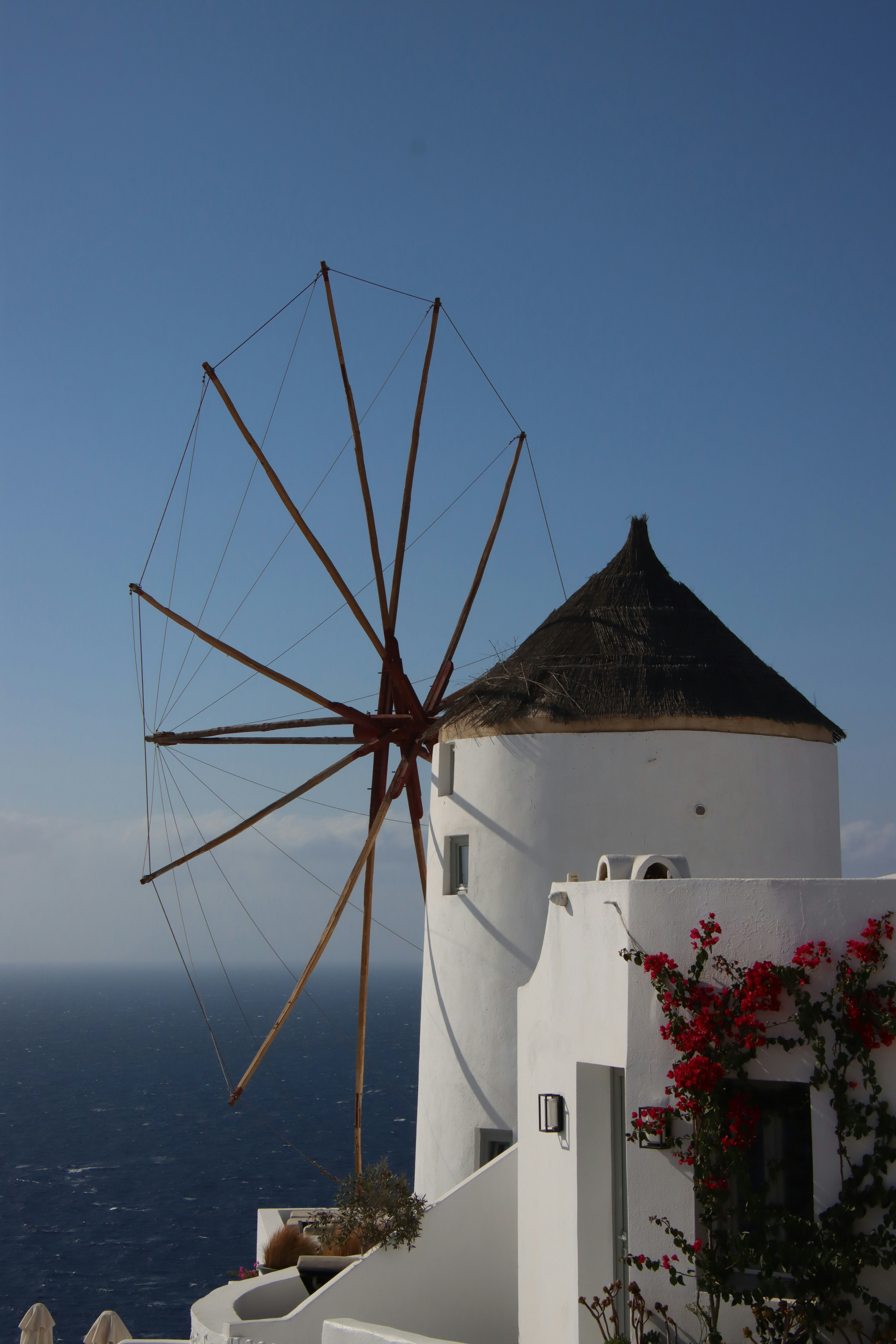 Aegean Windmill Portrait: White Walls, Wooden Sail Wheel, and Bougainvillea