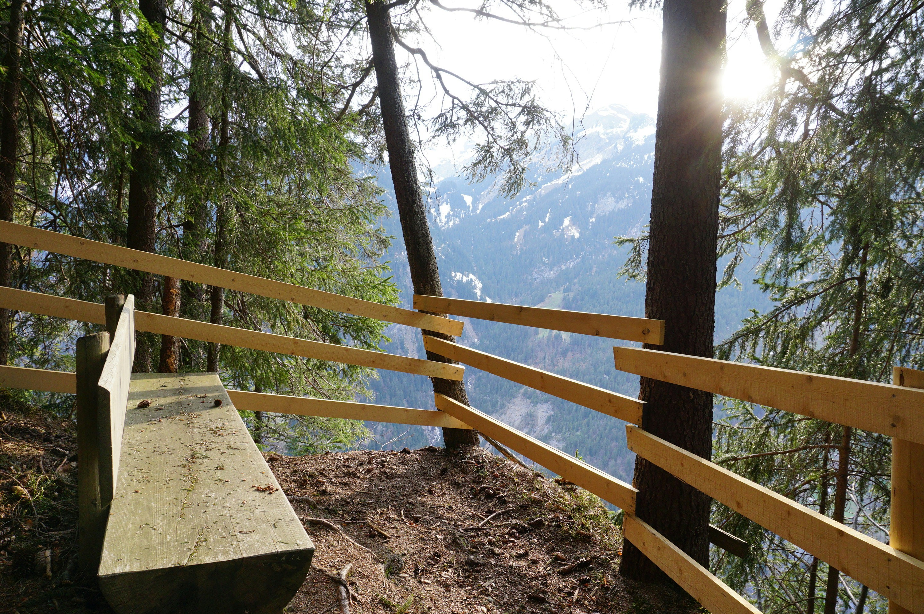 Sunlit Ridge Walk: A Wooden Barrier Overlooking a Mountain Valley
