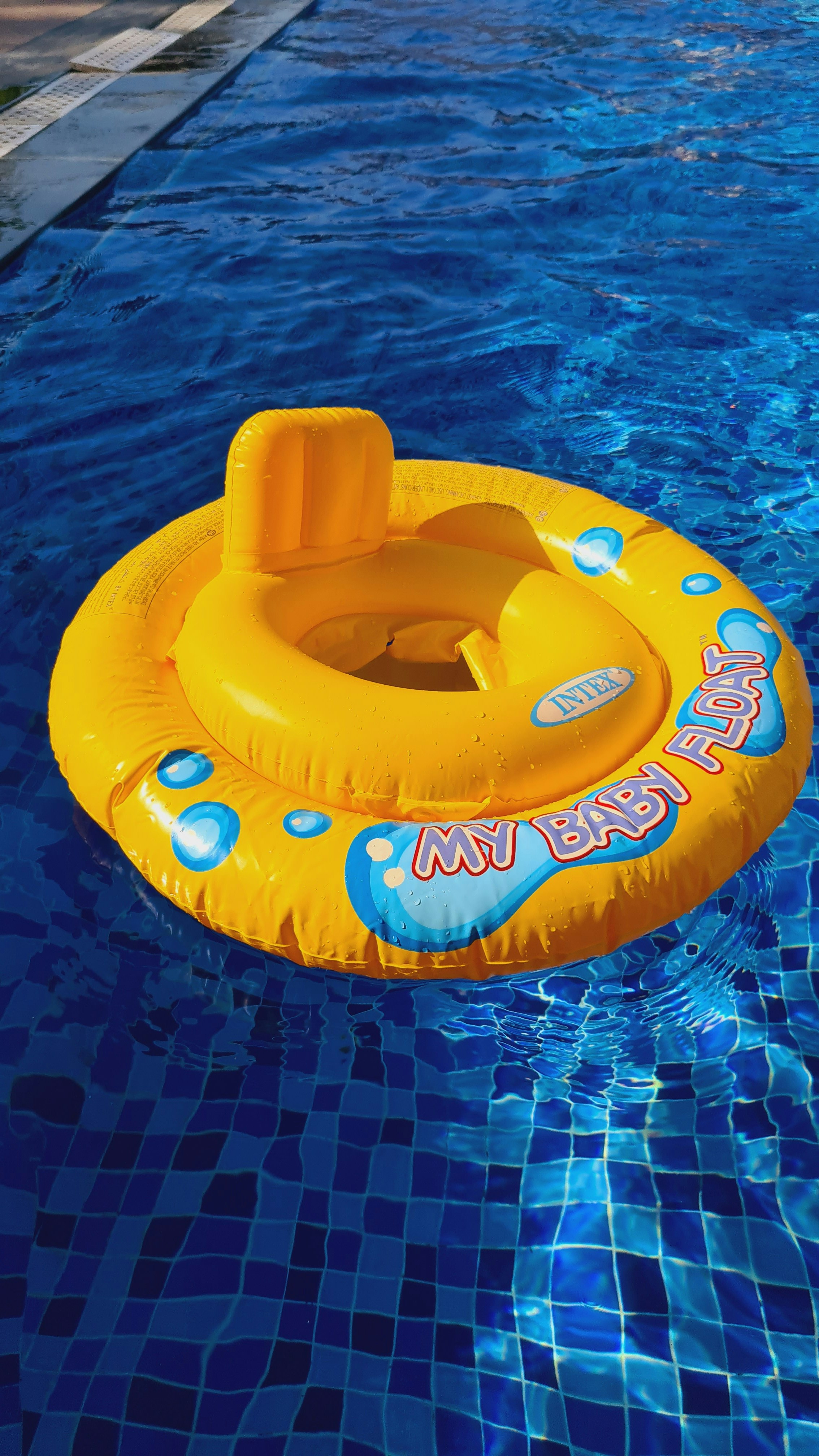 Yellow Life Ring Drifting in Sunlit Pool
