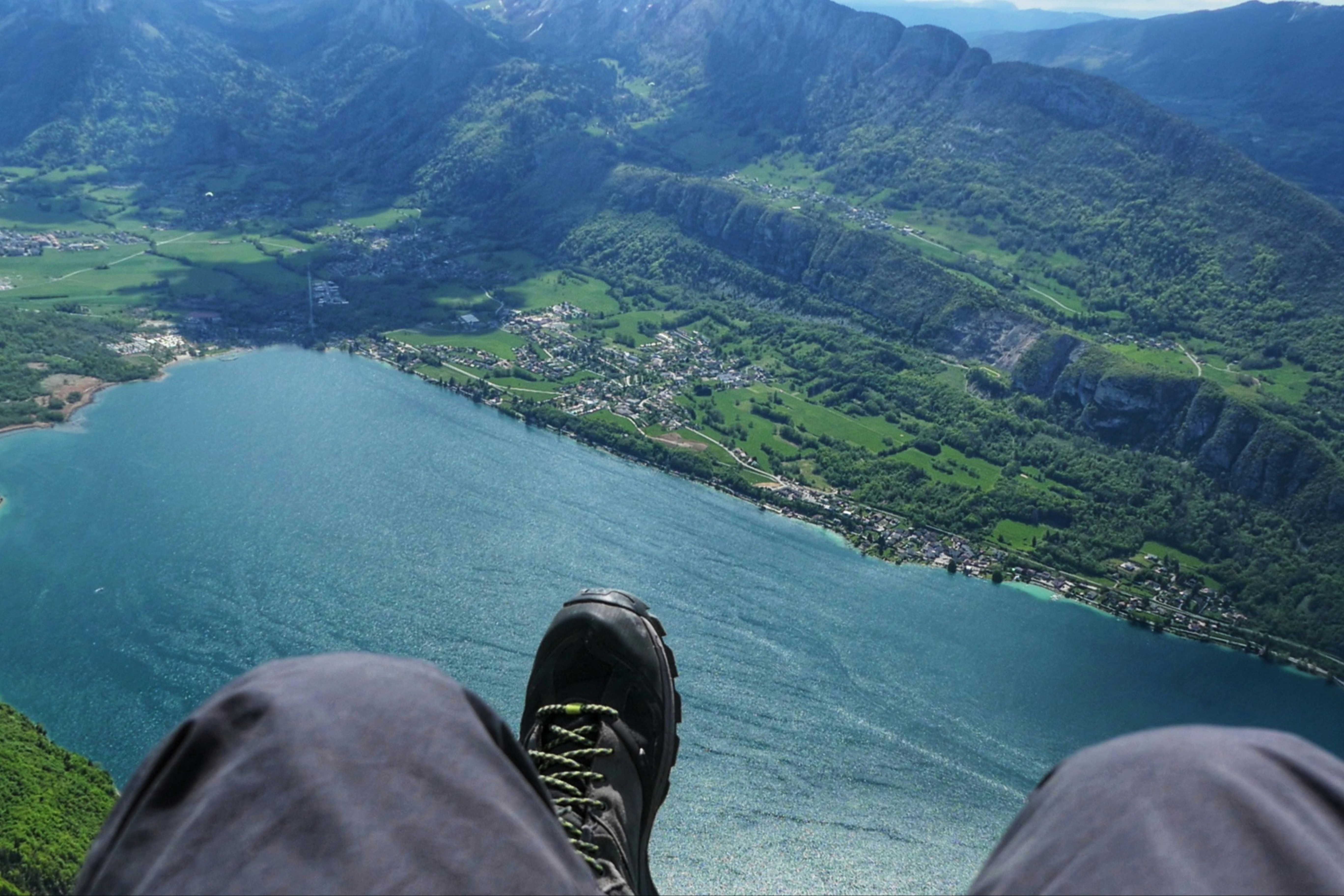 A person's feet on a cliff above a body of water photo – Free Apparel ...