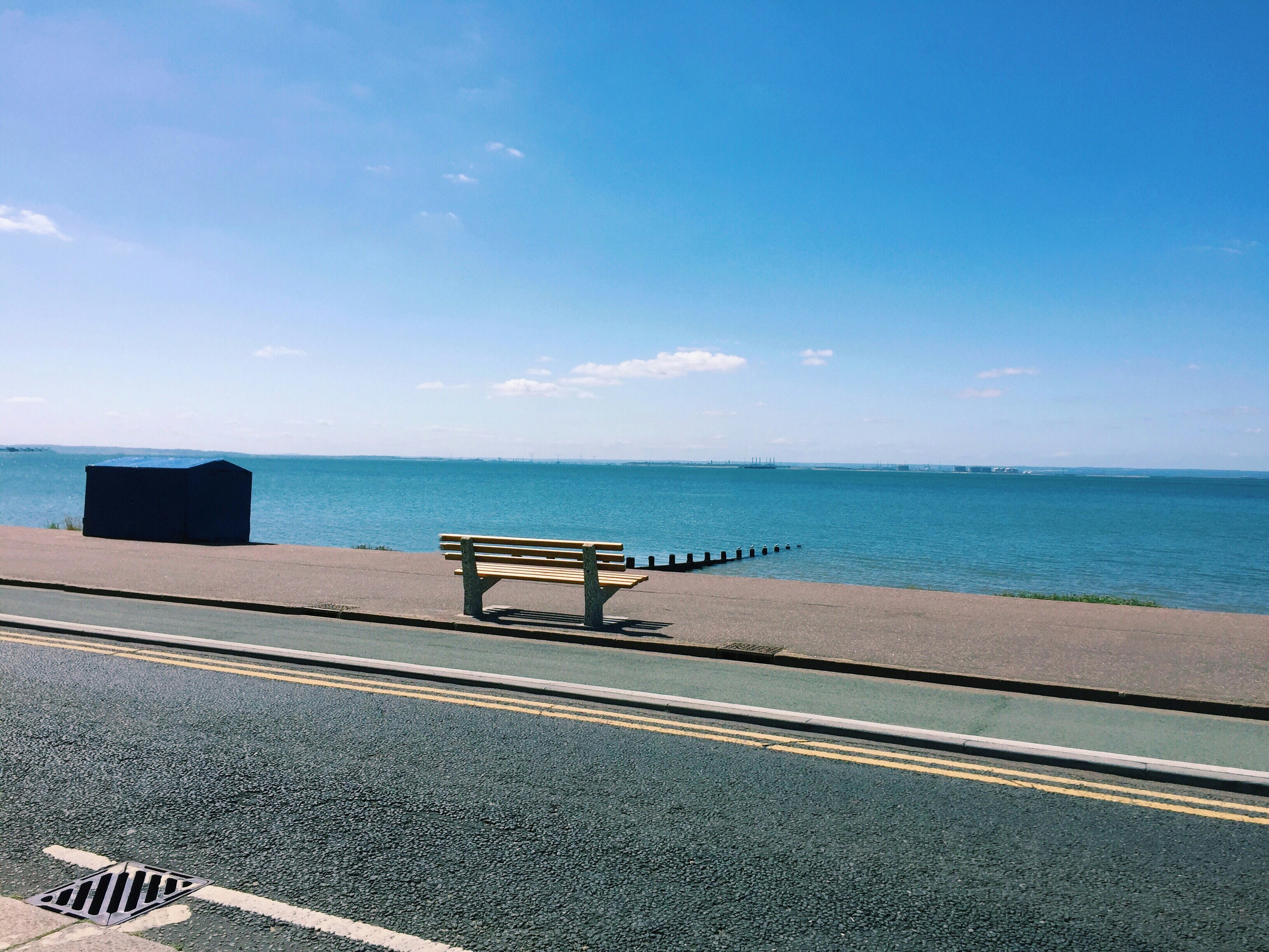 Edge of Calm: A Lone Bench Watches the Sea from a Quiet Promenade