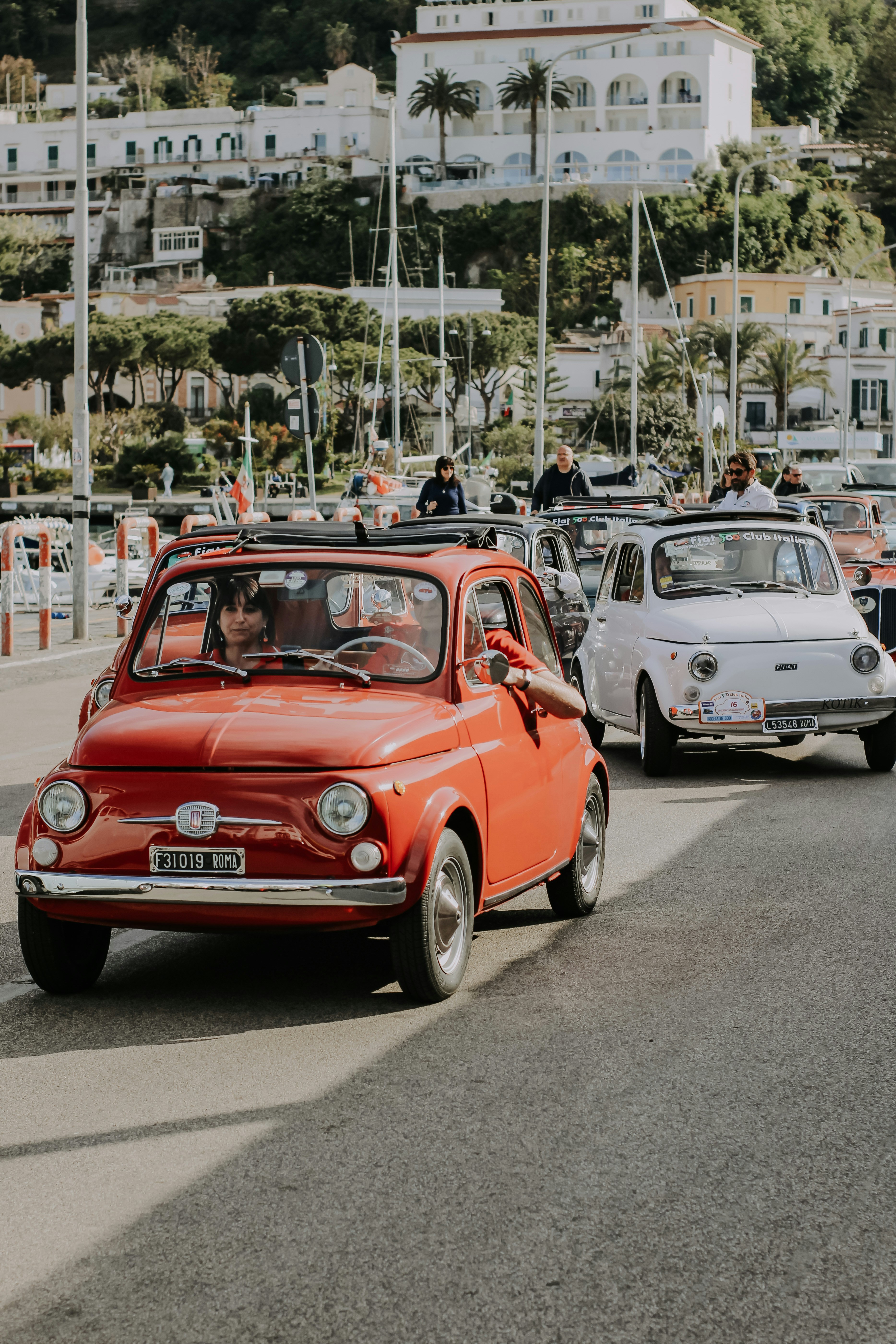Red Fiat 500 Leads a Coastal Parade Along a Mediterranean Seafront