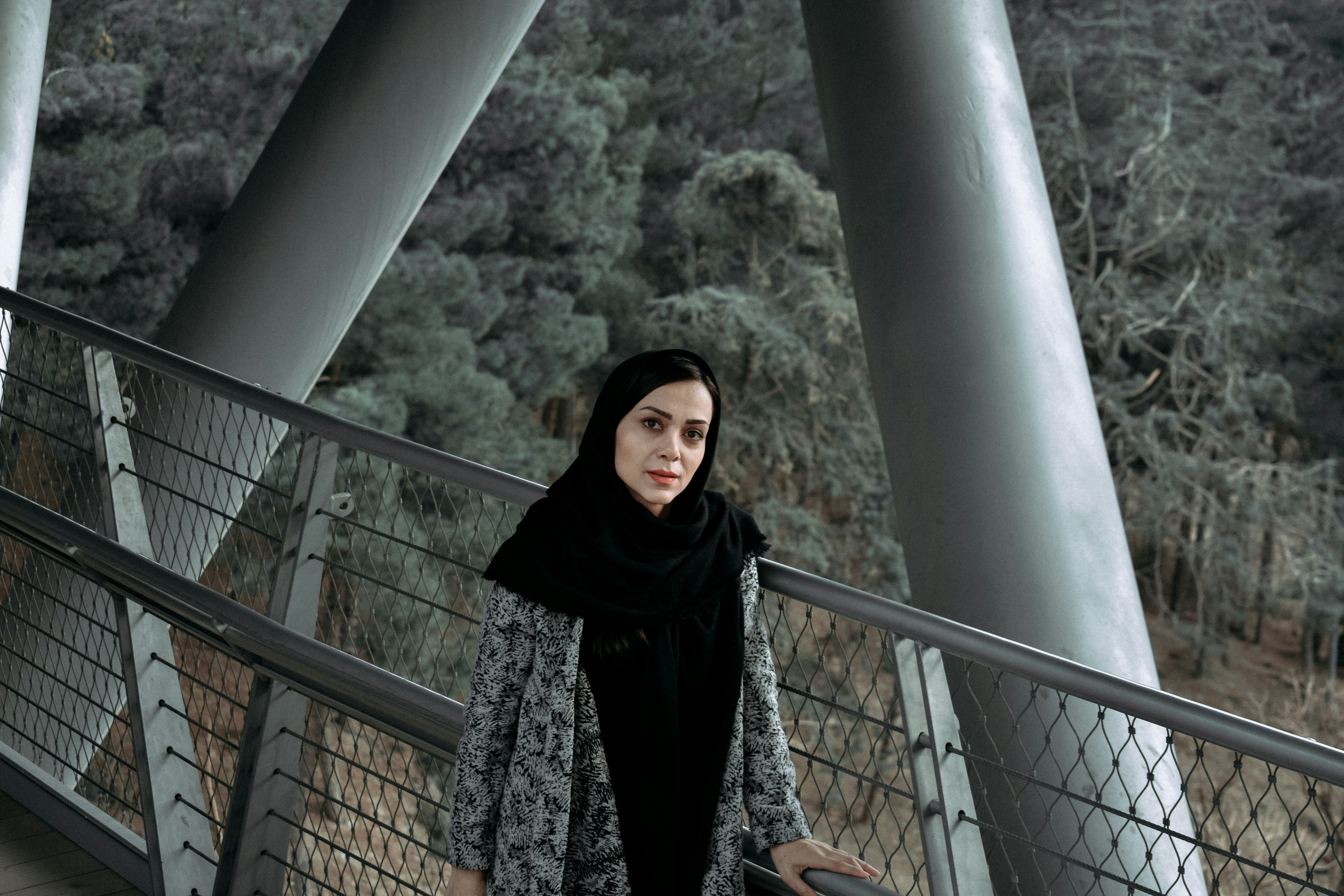 Woman in patterned coat on a covered walkway beneath diagonal beams