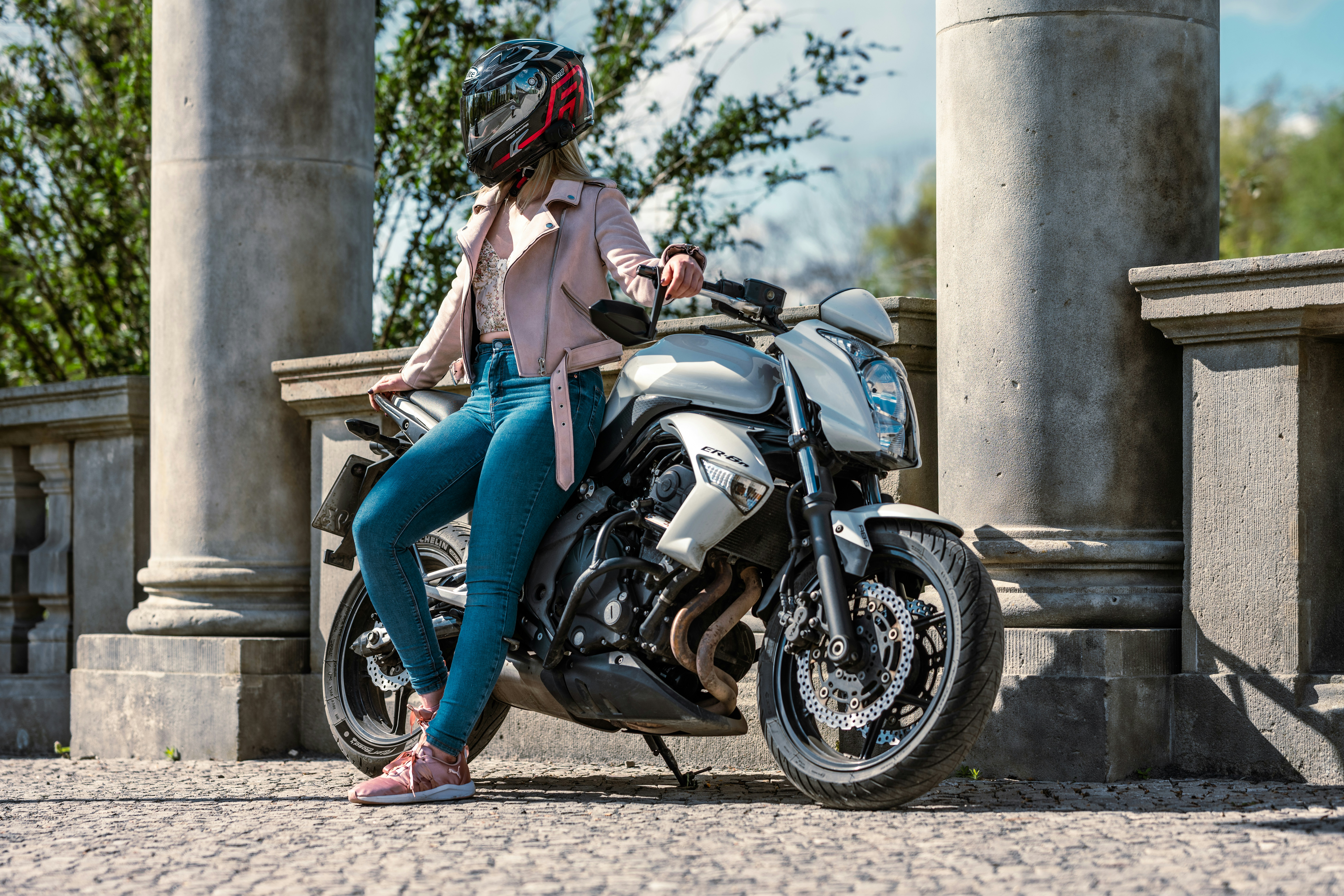 Between Columns and Chrome: a sunlit pause beside a silver motorcycle