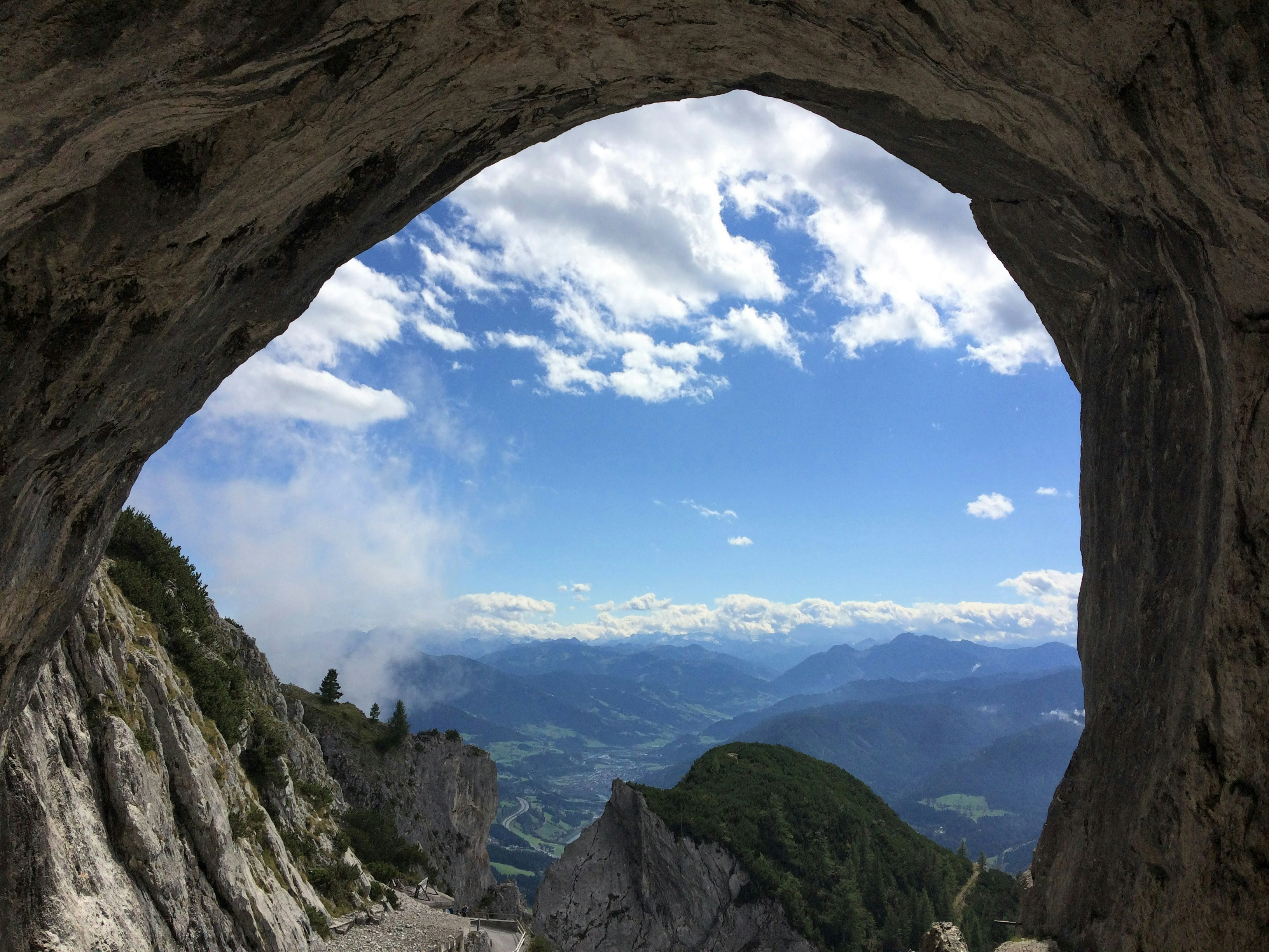 A view through a large rock archway at a valley below photo – Free Blue ...