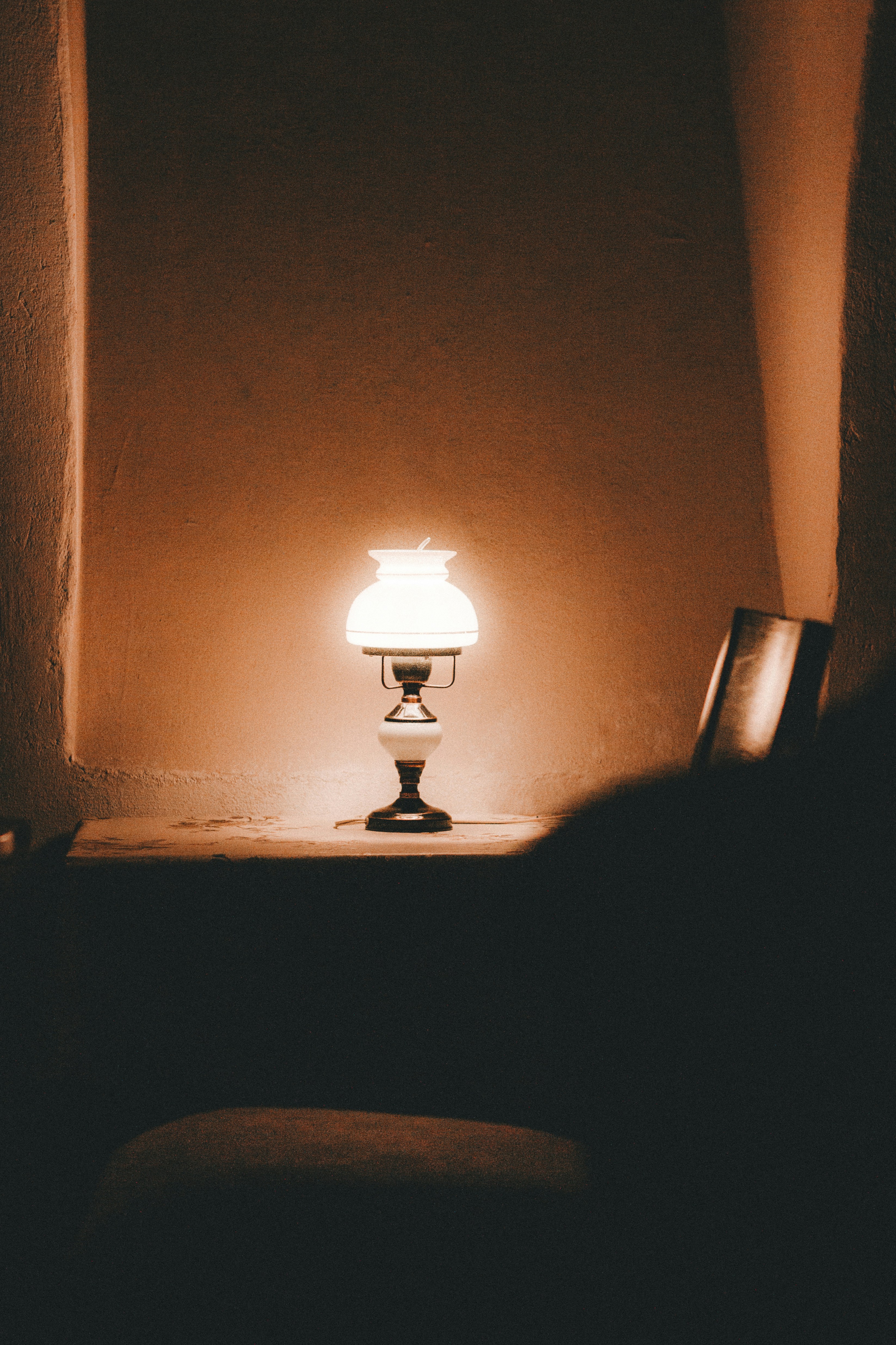 A vintage lamp softly illuminating a rustic table against a warm-toned wall, creating a serene atmosphere.
