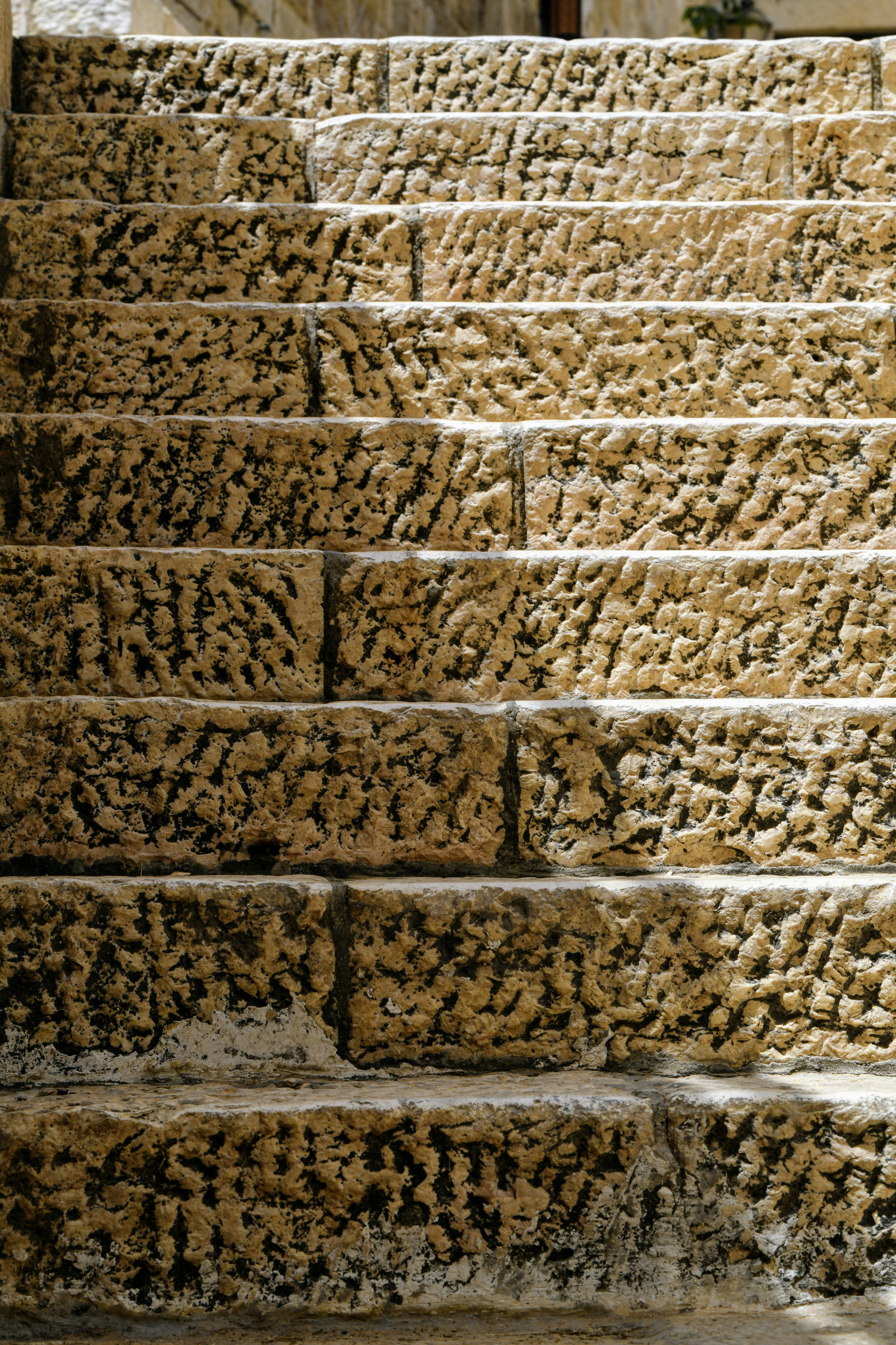 Weathered stone steps showcasing intricate textures and patterns, leading upward in a historic setting.