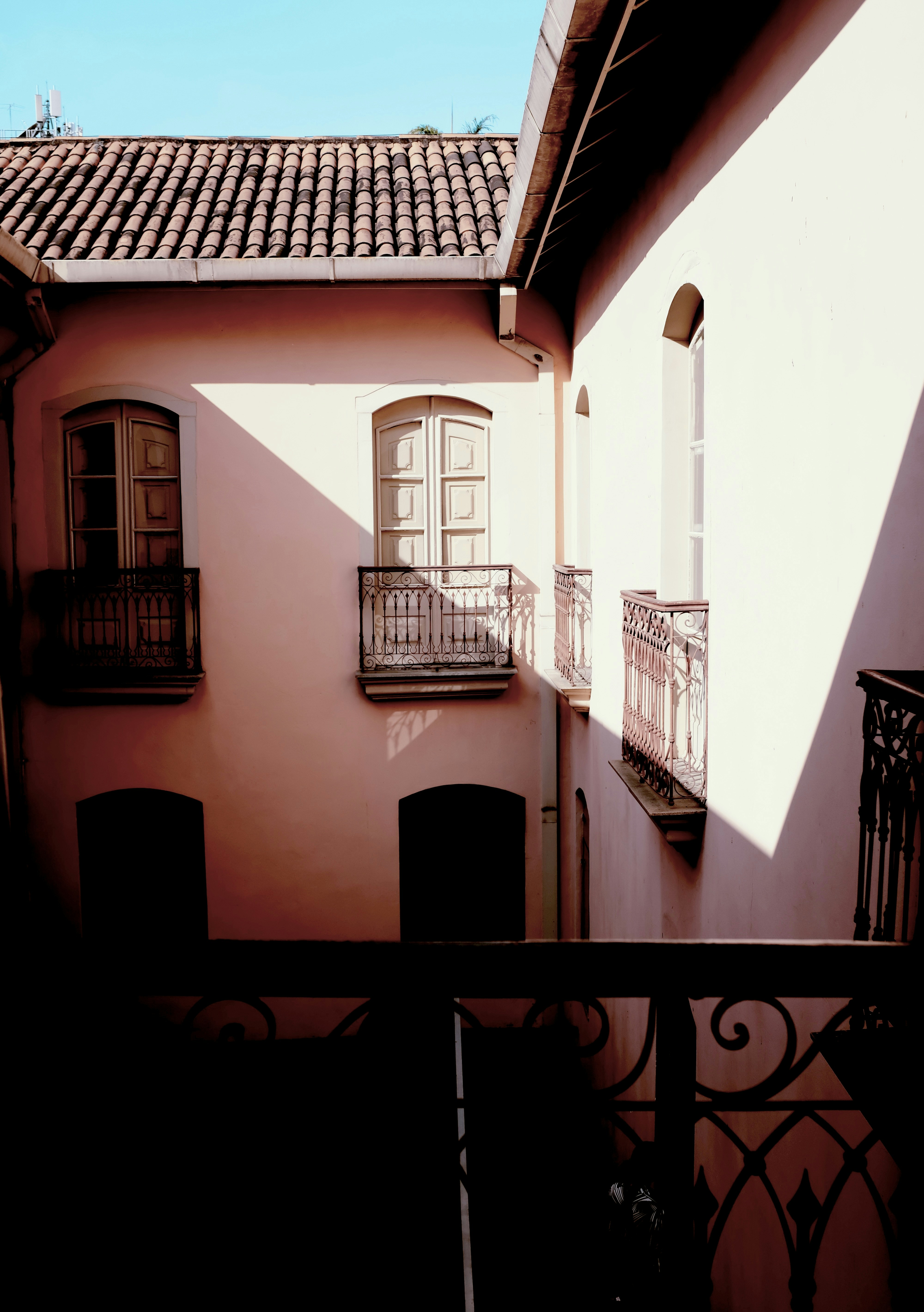 Sunlit Pink Courtyard: Geometry of Balconies and Shadows