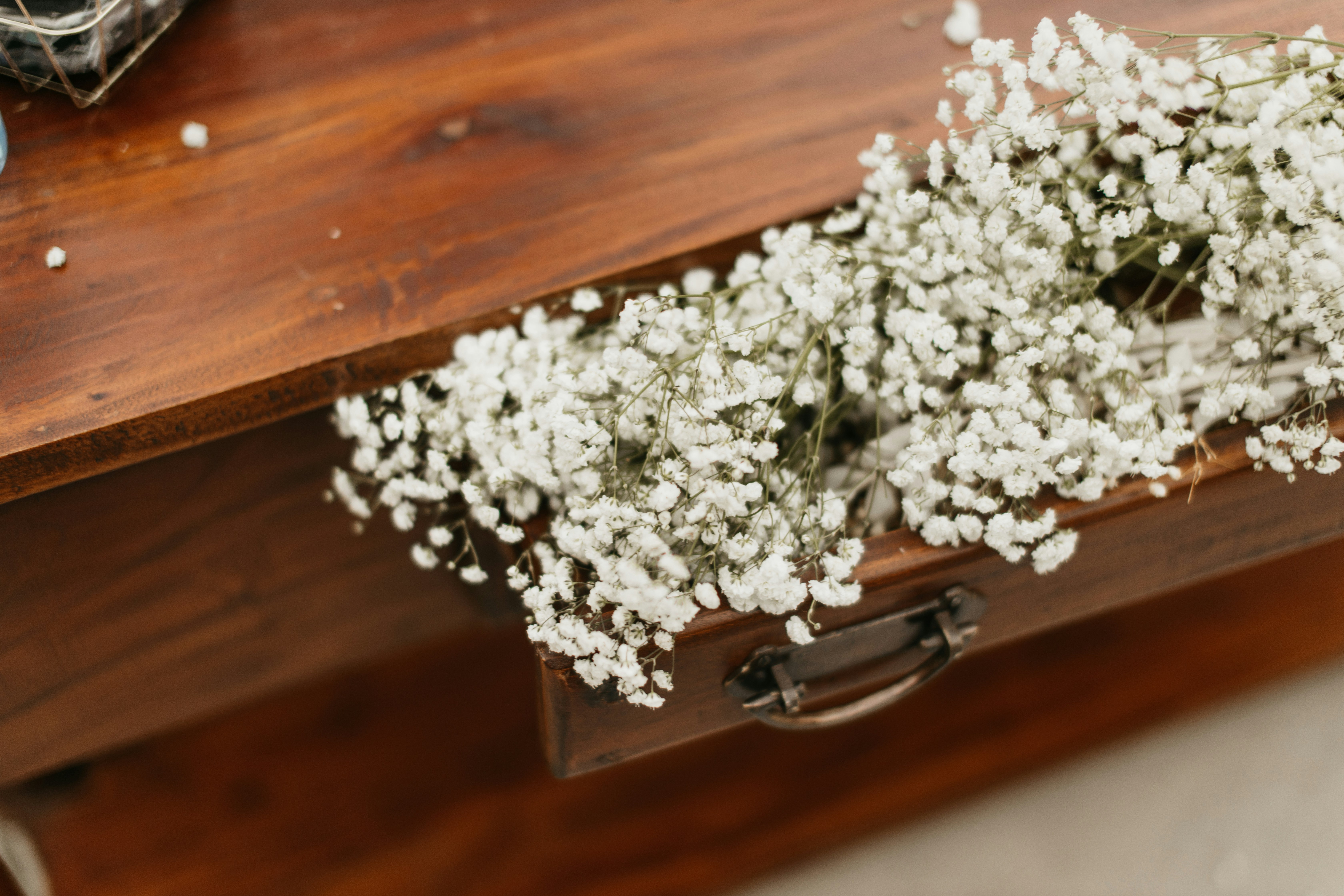 Delicate white flowers spilling from an open drawer on a rustic wooden surface. The arrangement evokes a serene atmosphere.
