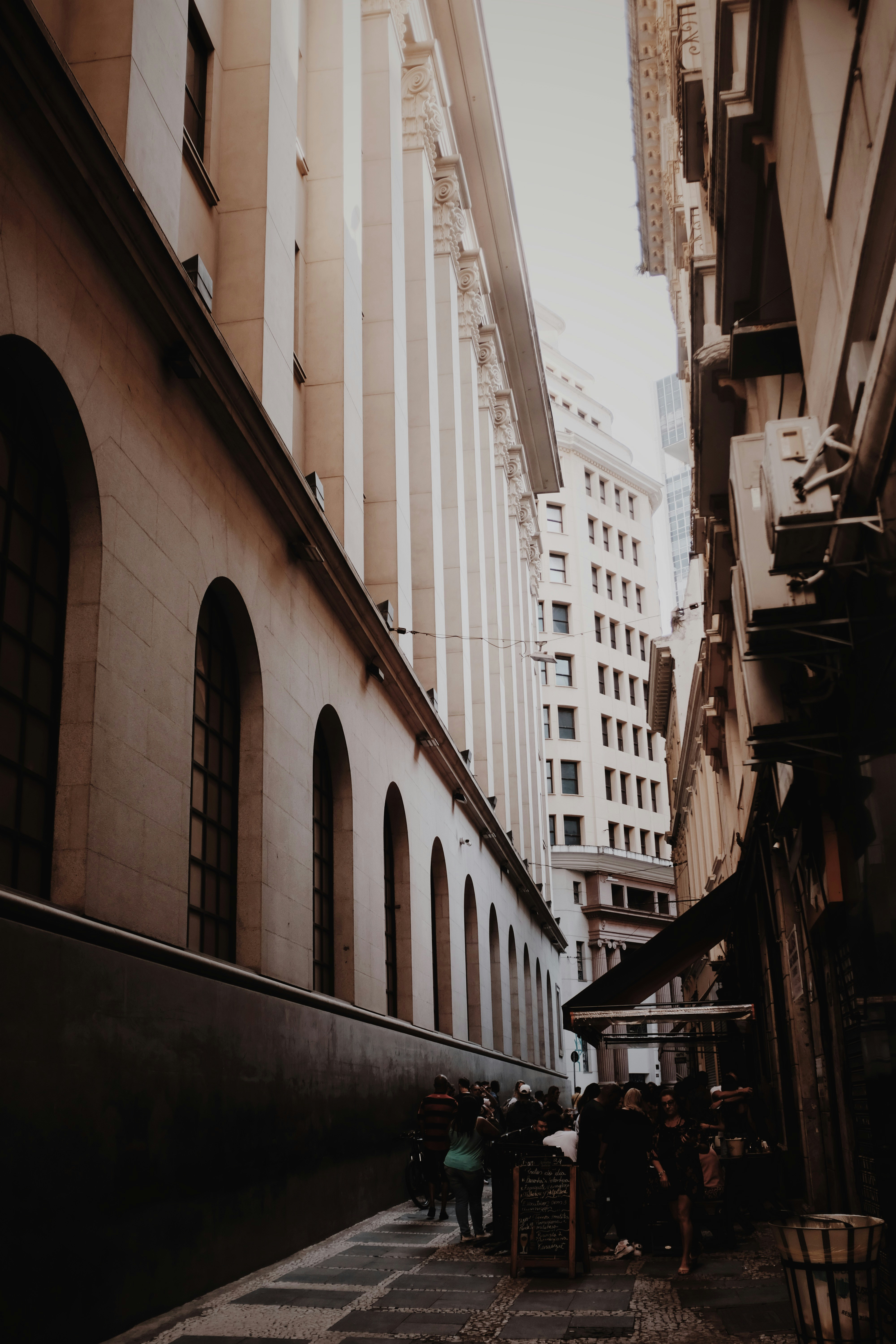 A group of people standing in a street between buildings photo – Free ...