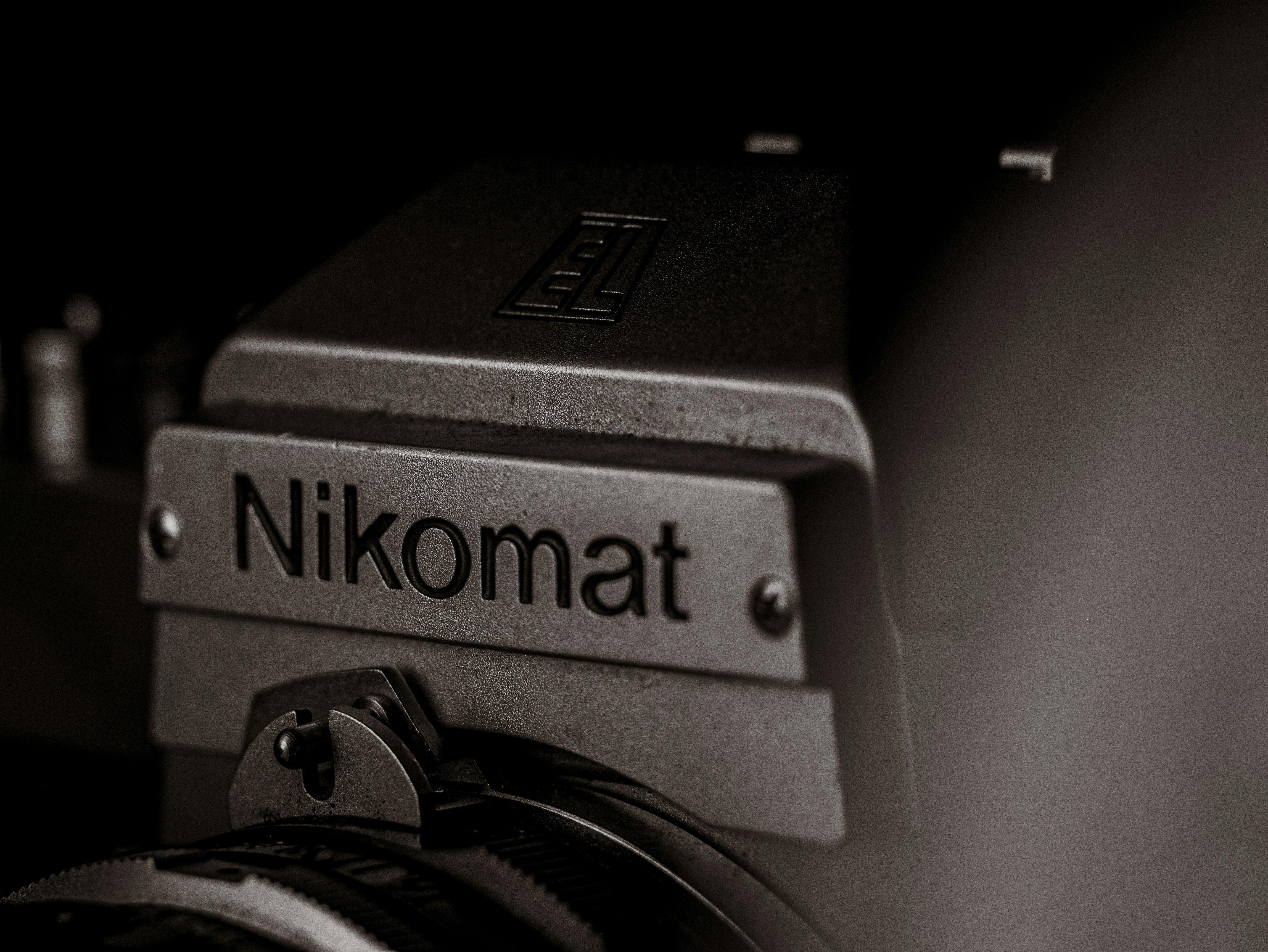 Close-up of a Nikomat camera showcasing its engraved logo and detailed design elements. The shot emphasizes the vintage craftsmanship of this iconic film camera.