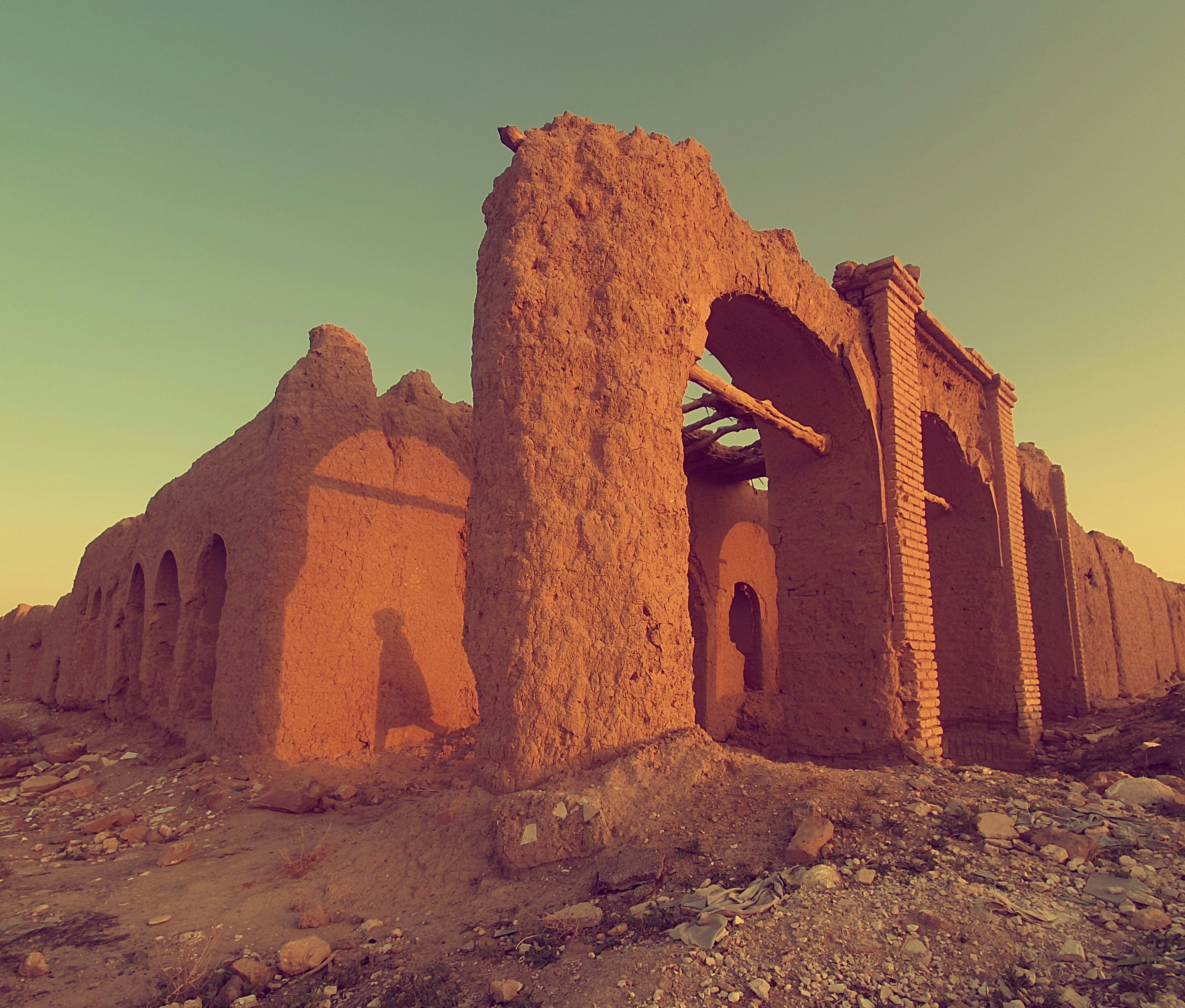 Weathered adobe ruins bathed in golden light, revealing arches and textures of a bygone era.