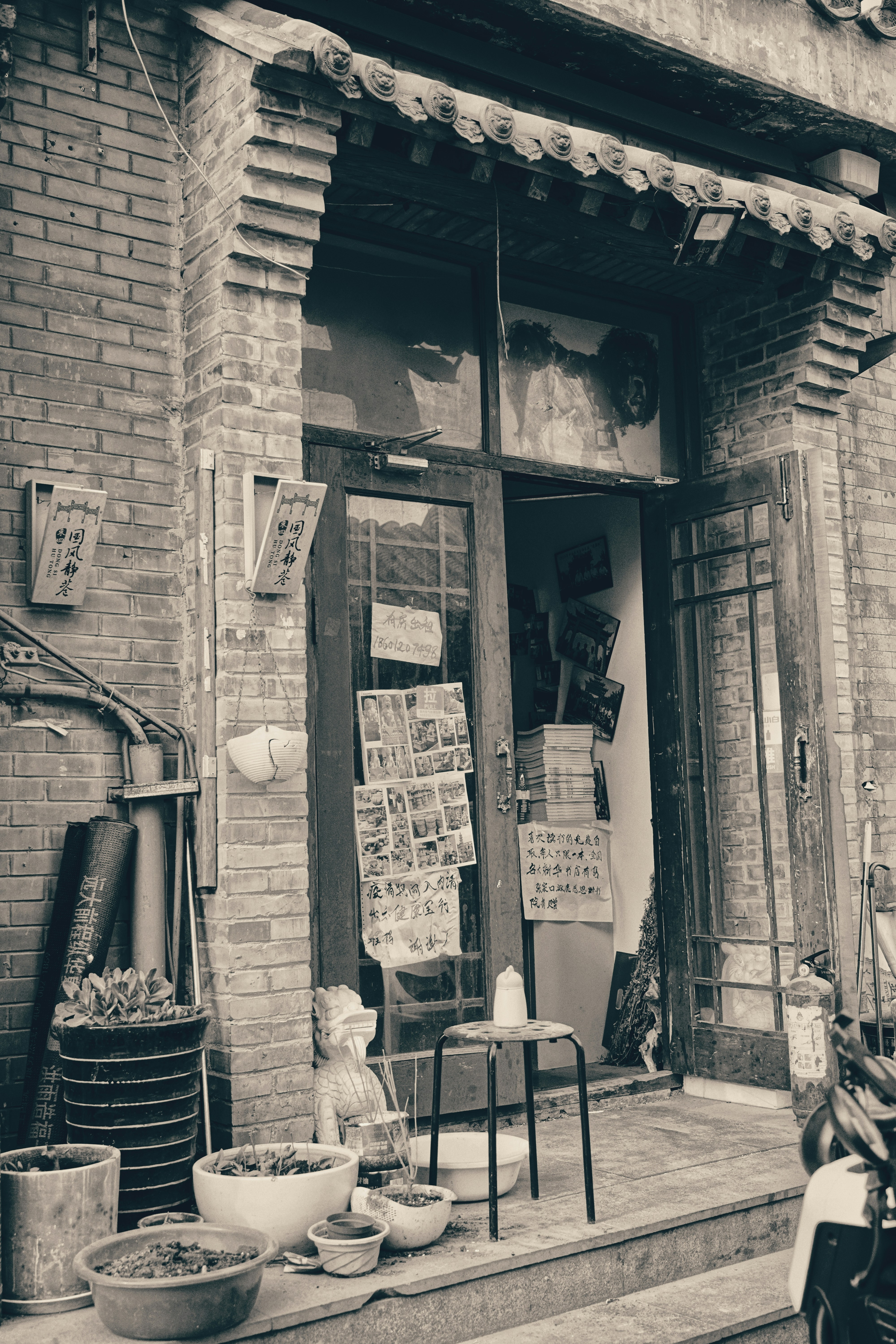 Doorway Notes: A Weathered Shopfront Framed by Brick, Posters, and Pots