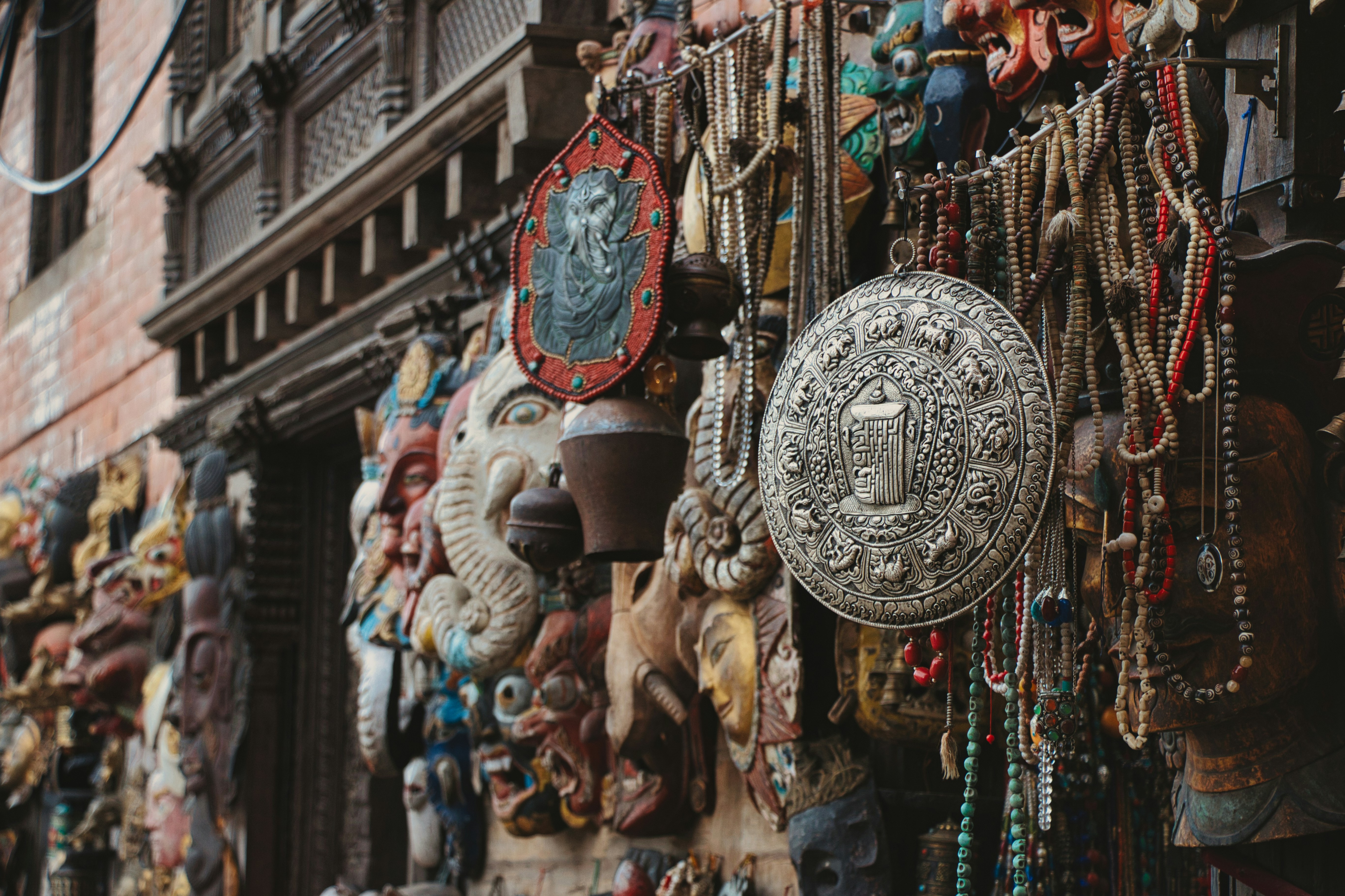 Intricately carved masks and handcrafted jewelry adorn a vibrant market wall, showcasing the rich craftsmanship of local artisans.