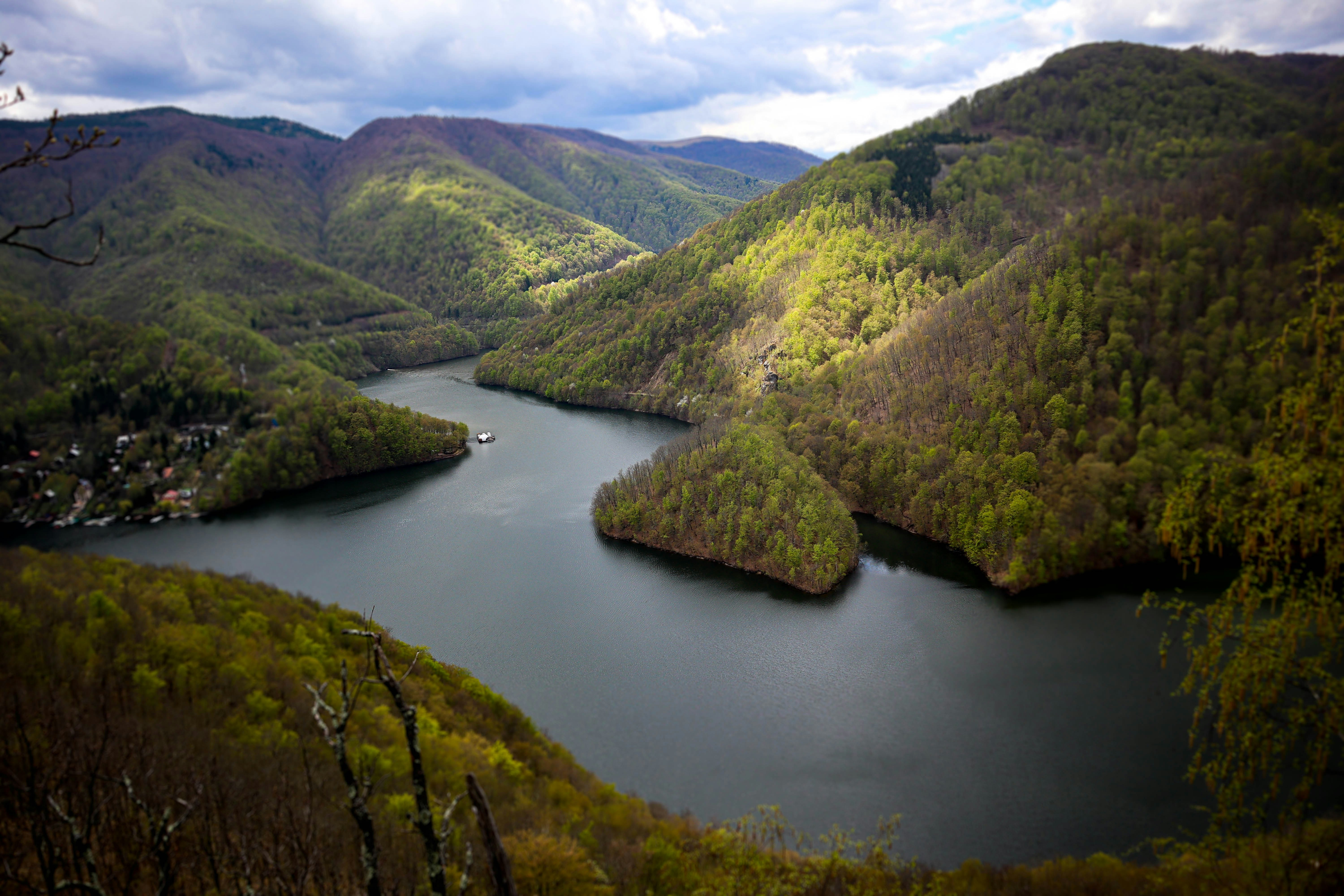 Lush green hills envelop a winding river under a partly cloudy sky.