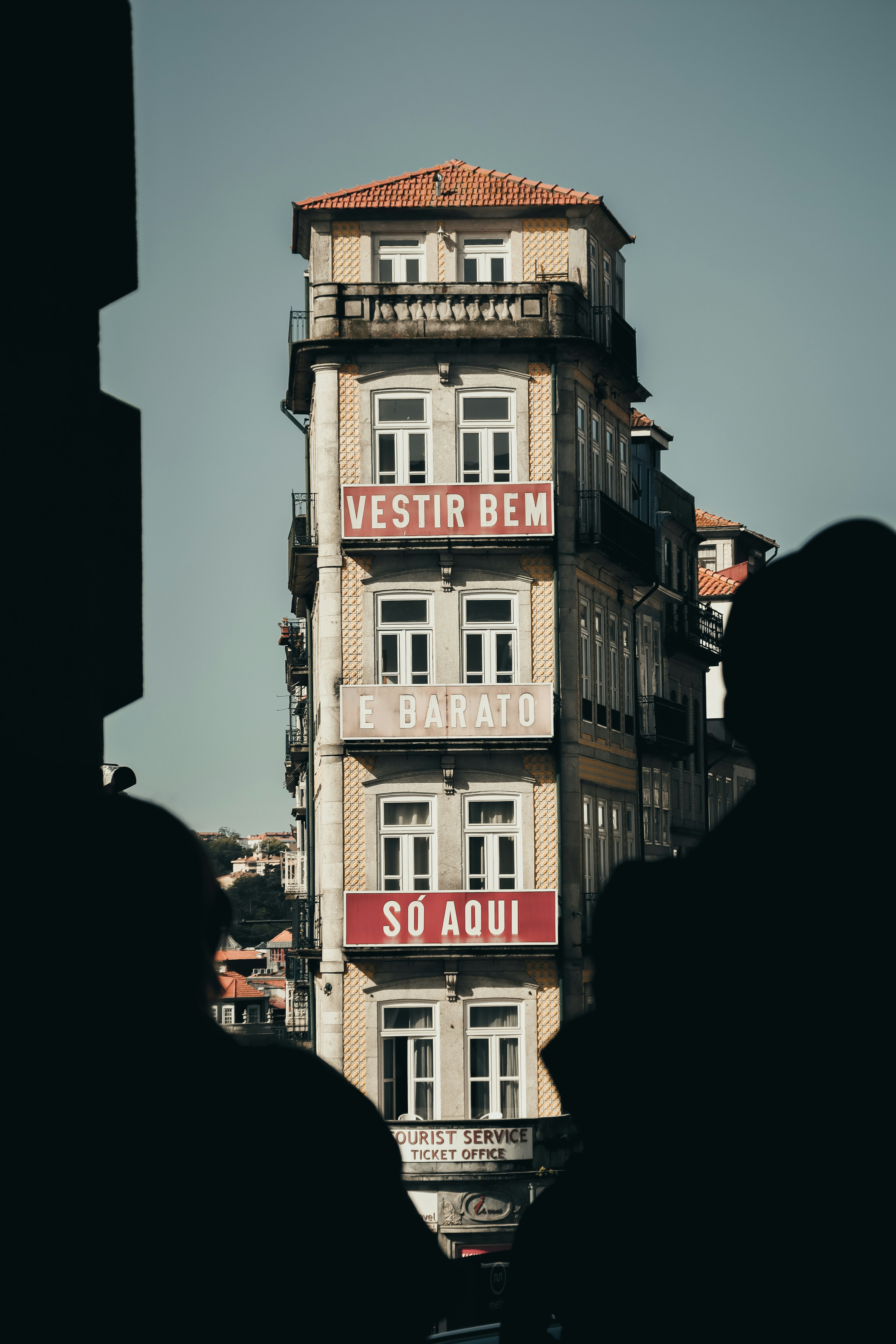 Balcony Signage on a Lisbon building framed by silhouetted passersby