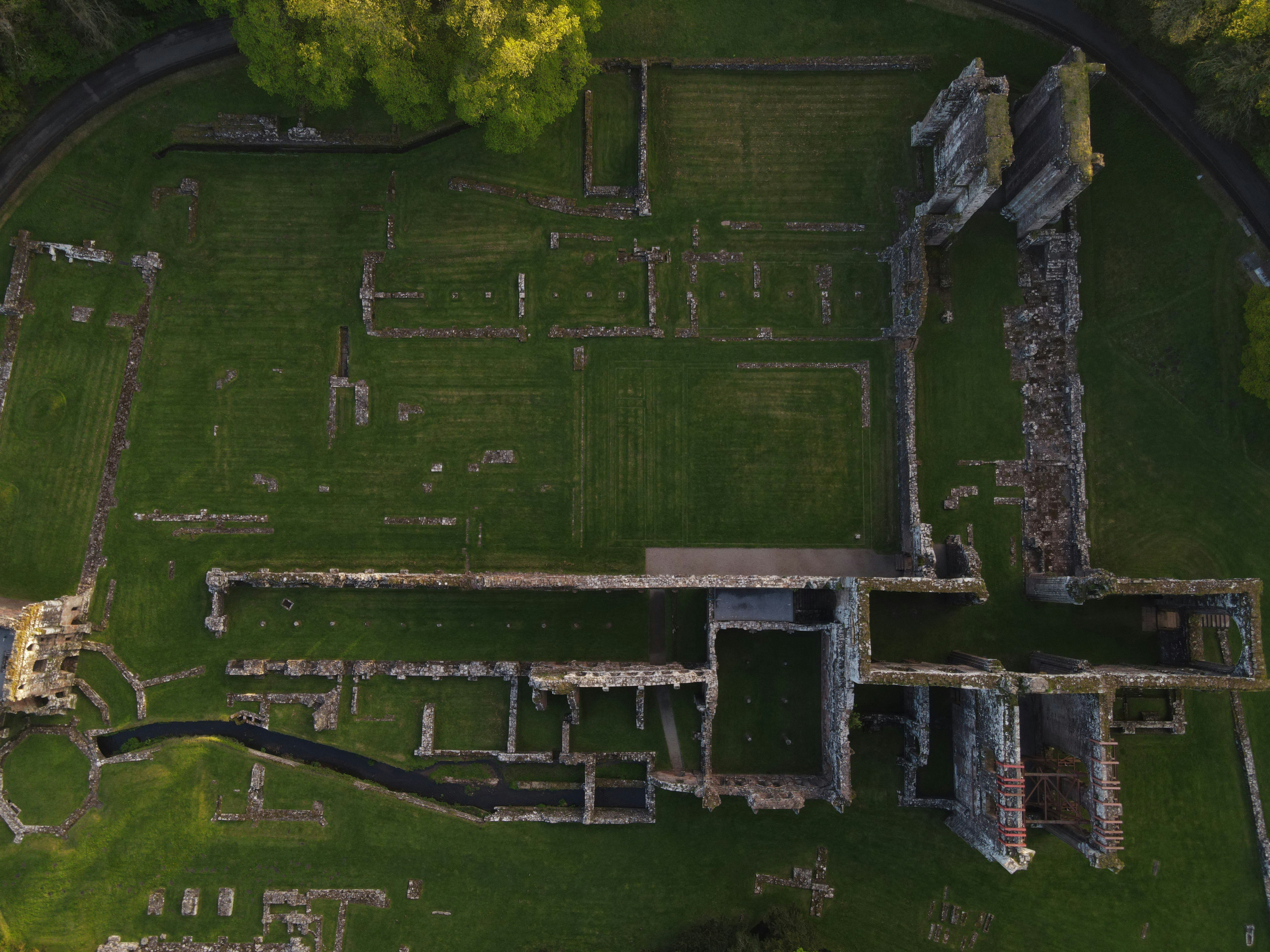 Aerial view of ancient ruins surrounded by lush greenery, showcasing the remnants of historical architecture and layout.